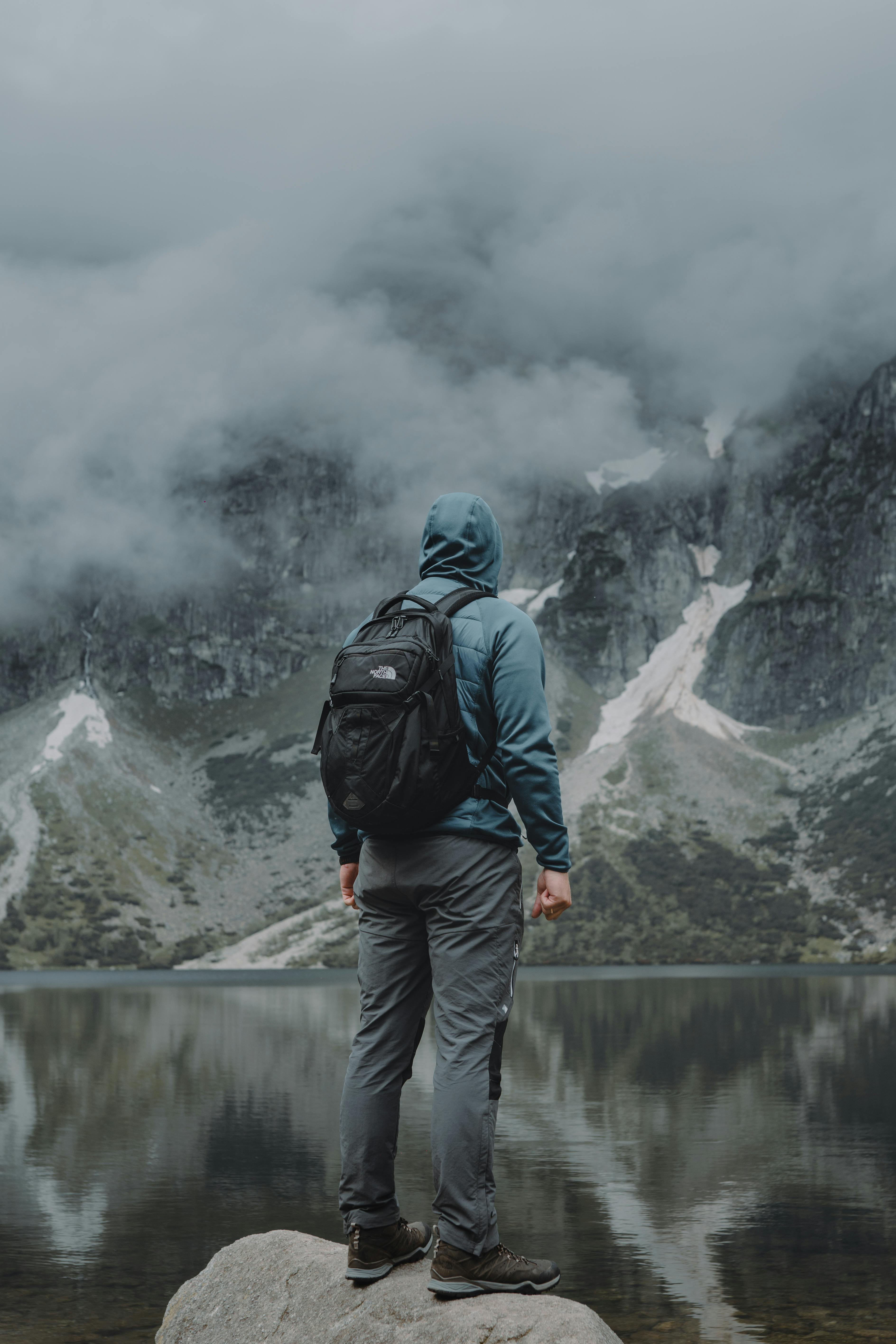 Man Standing on a Rock Near a Lake · Free Stock Photo