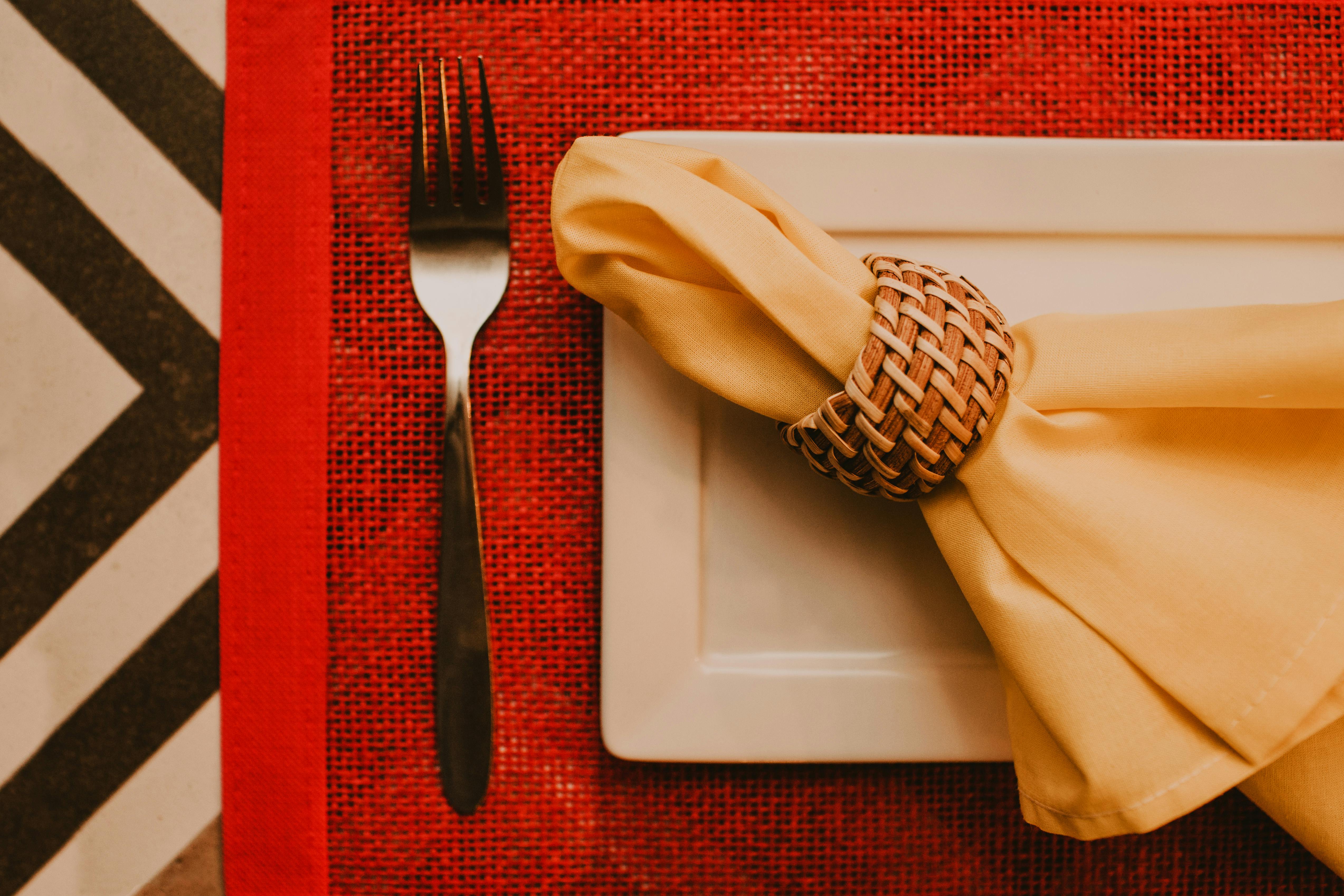 Elegant table set with napkin on plate on red place mat · Free Stock Photo