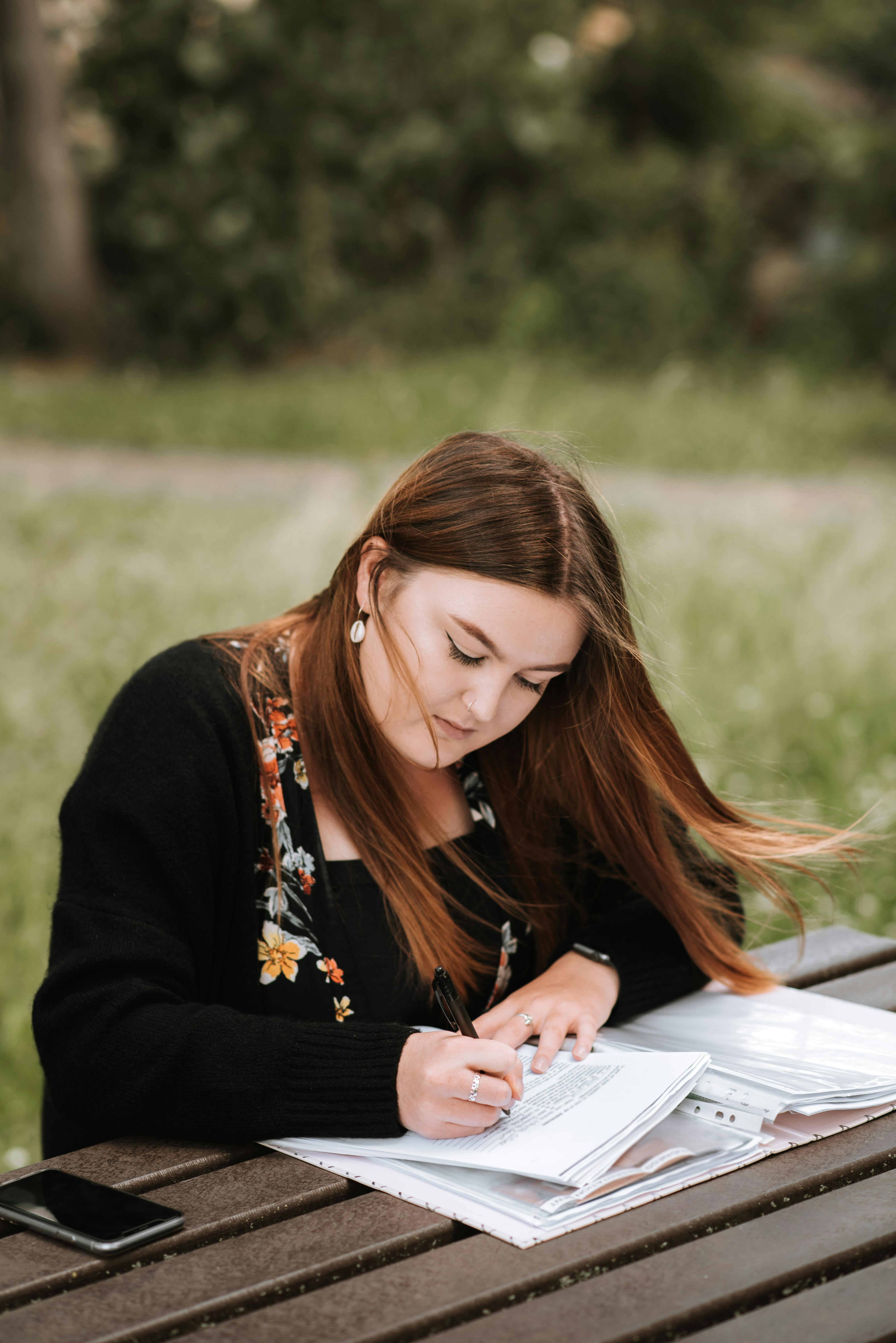 Concentrated student doing homework in park · Free Stock Photo