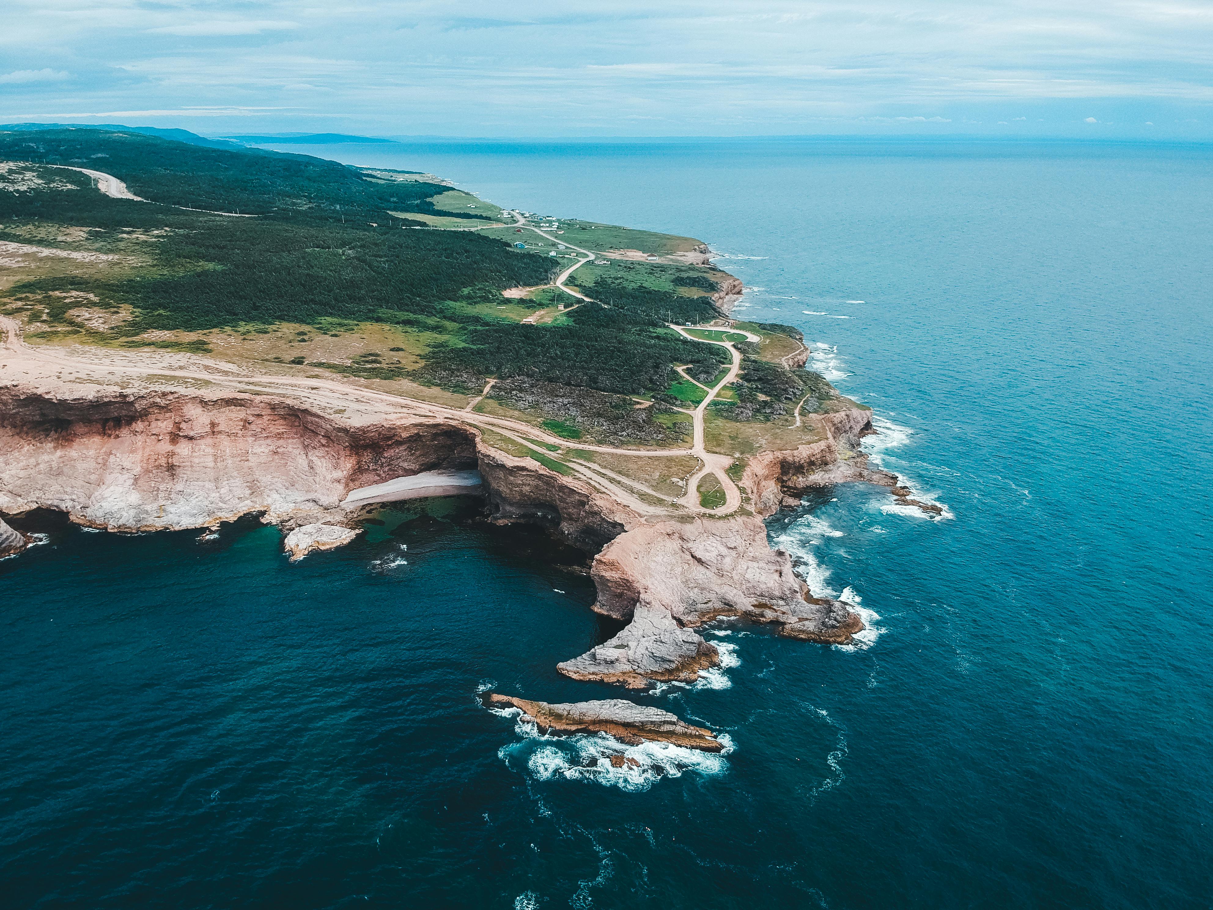Turquoise sea coast surrounded by rocky cliff covered with lush trees ...