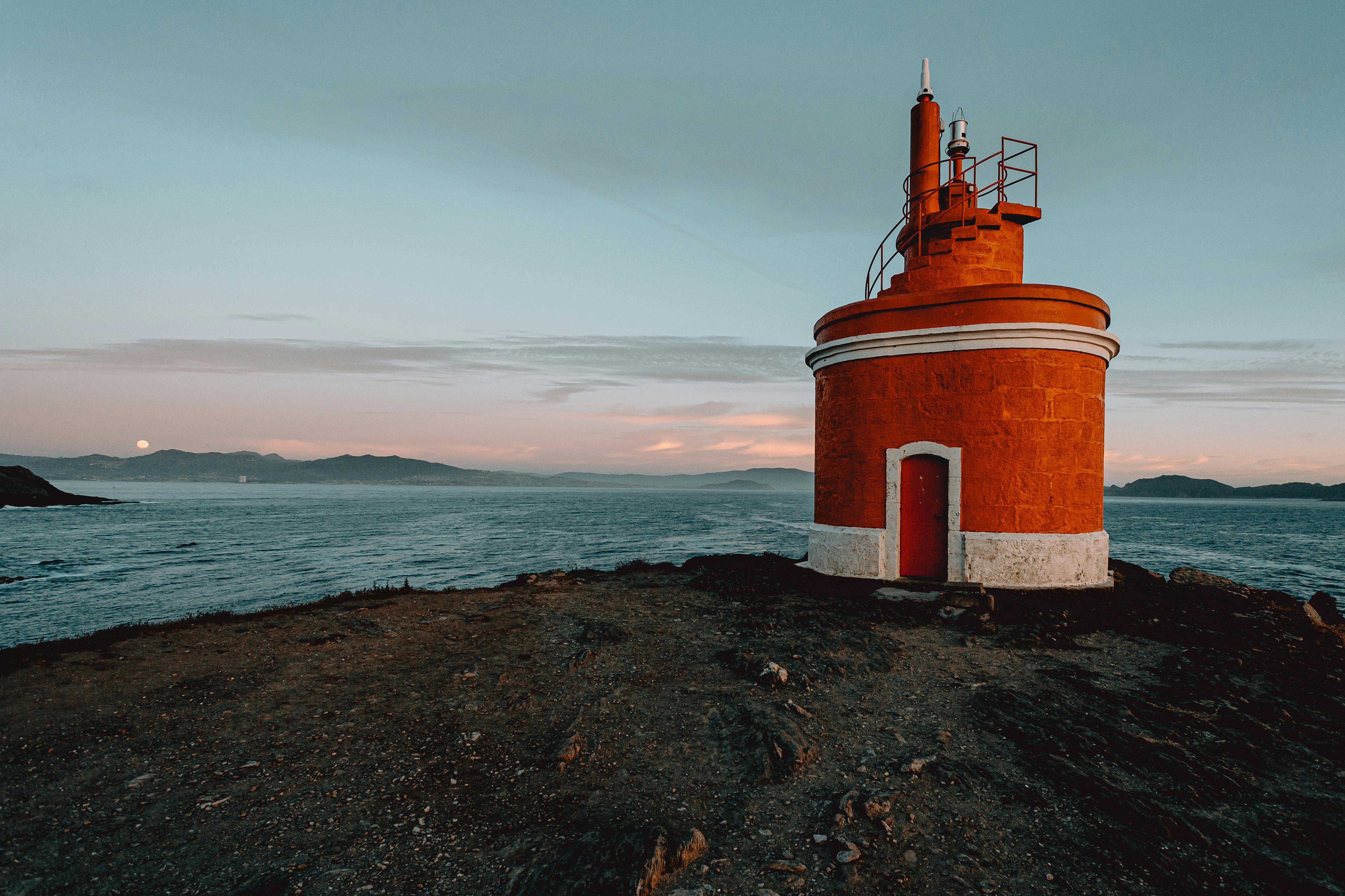 Small red lighthouse on rocky coastline · Free Stock Photo