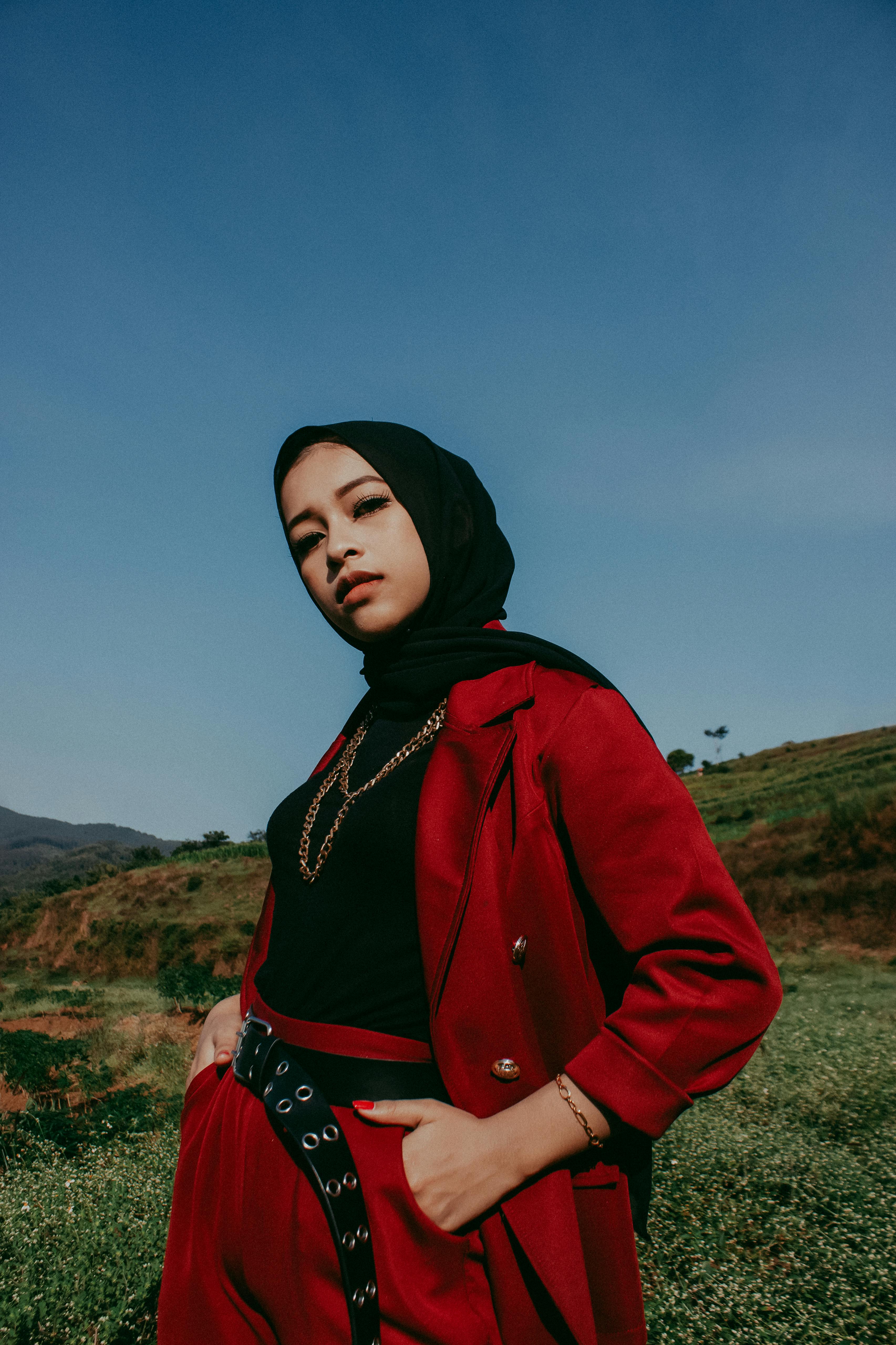 Woman in Red Coat and Black Hijab Standing on a Field · Free Stock Photo
