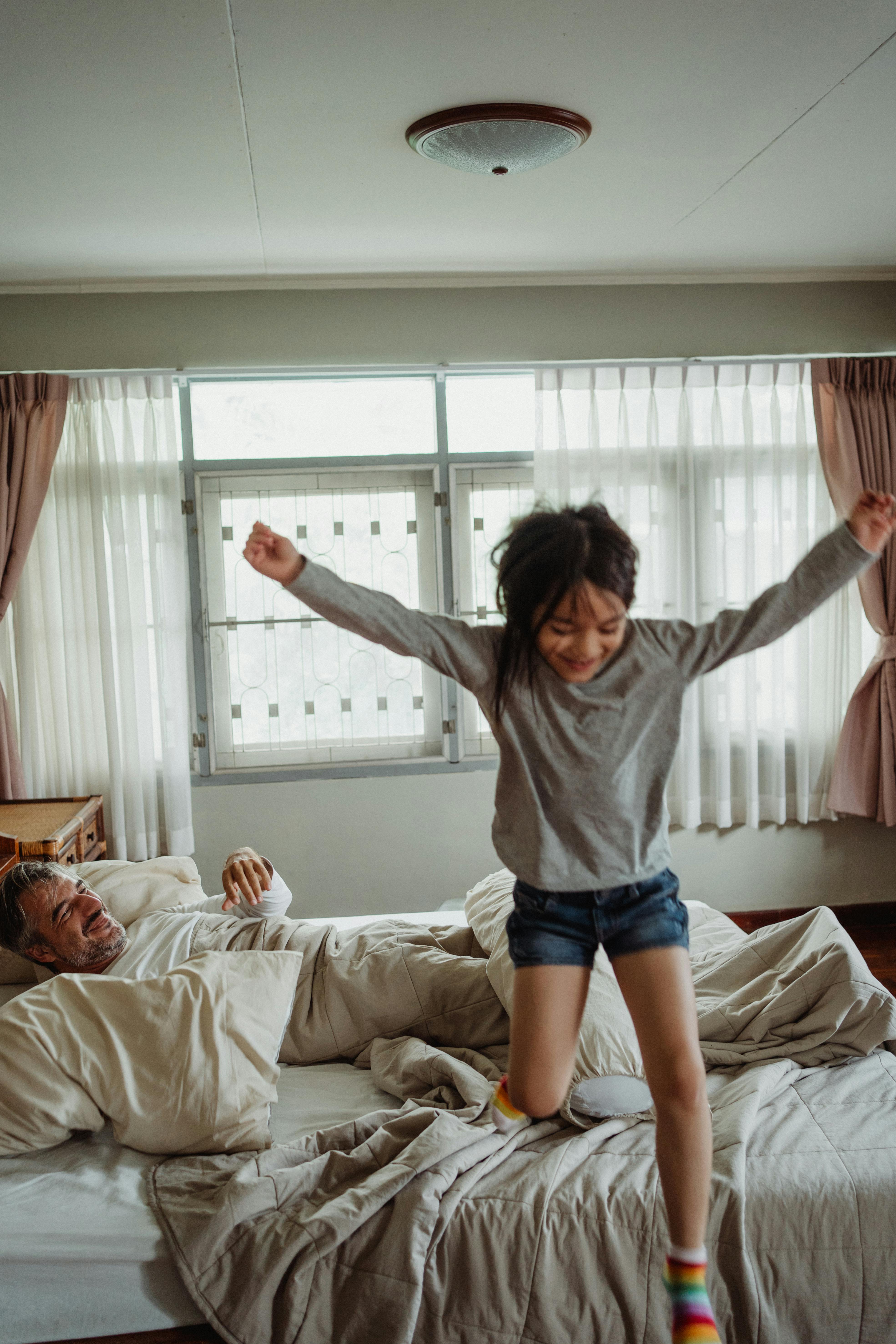A Girl in Gray Long Sleeves Jumping Out of Bed · Free Stock Photo