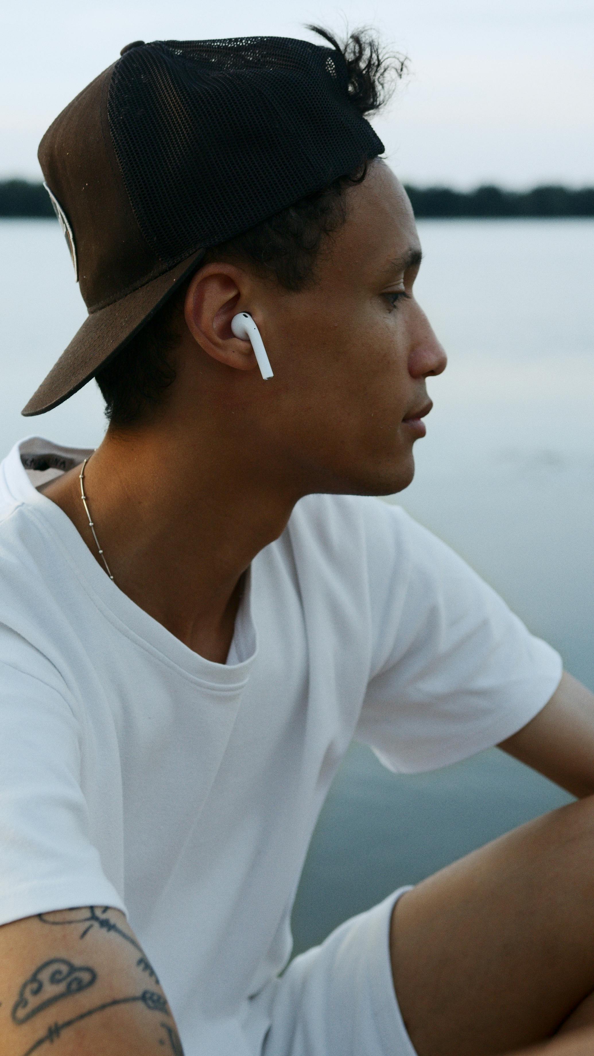 Man in White Shirt and Cap Wearing a Wireless Earpods · Free Stock Photo