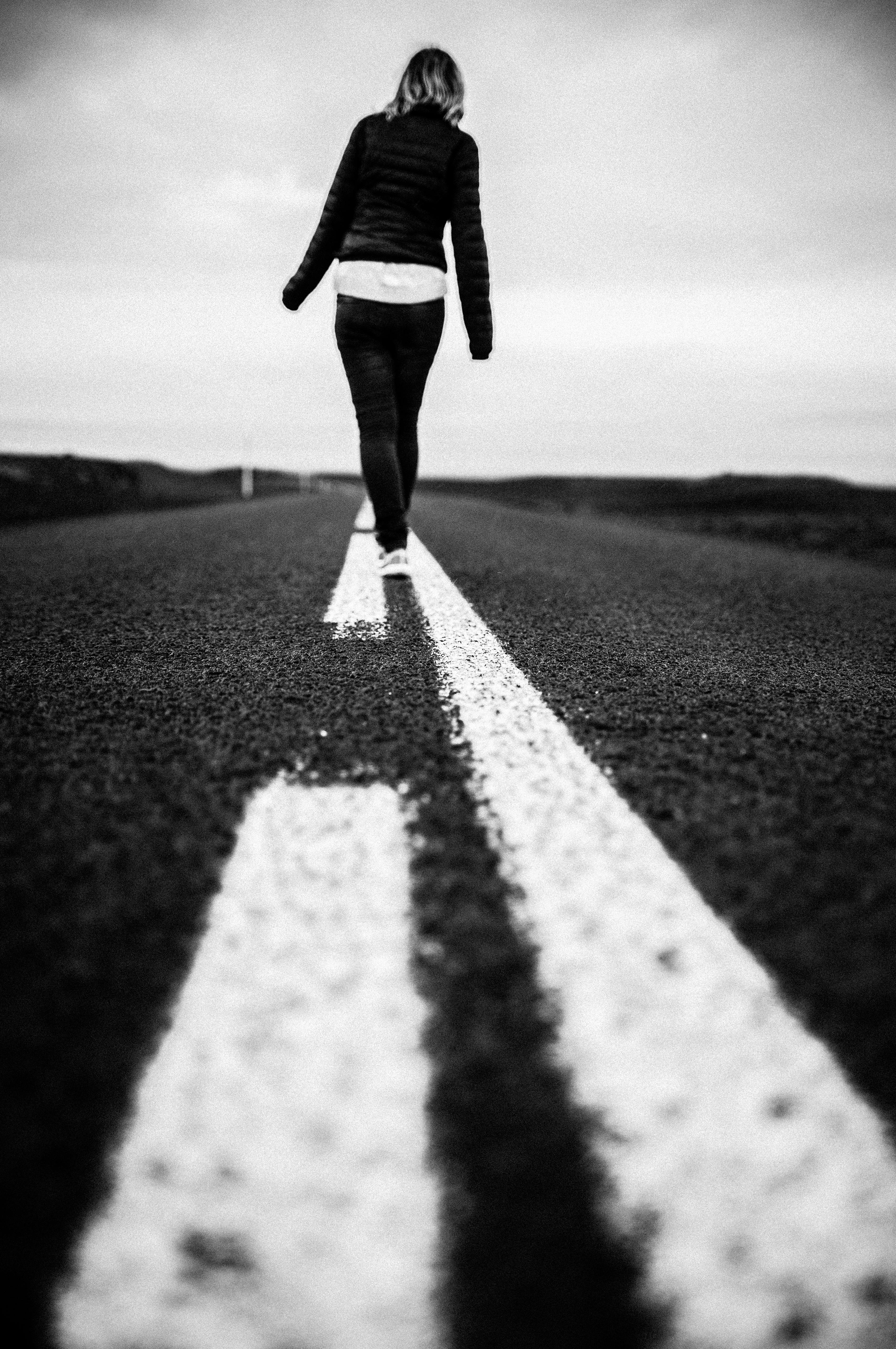Faceless woman walking on spotted line on asphalt road · Free Stock Photo