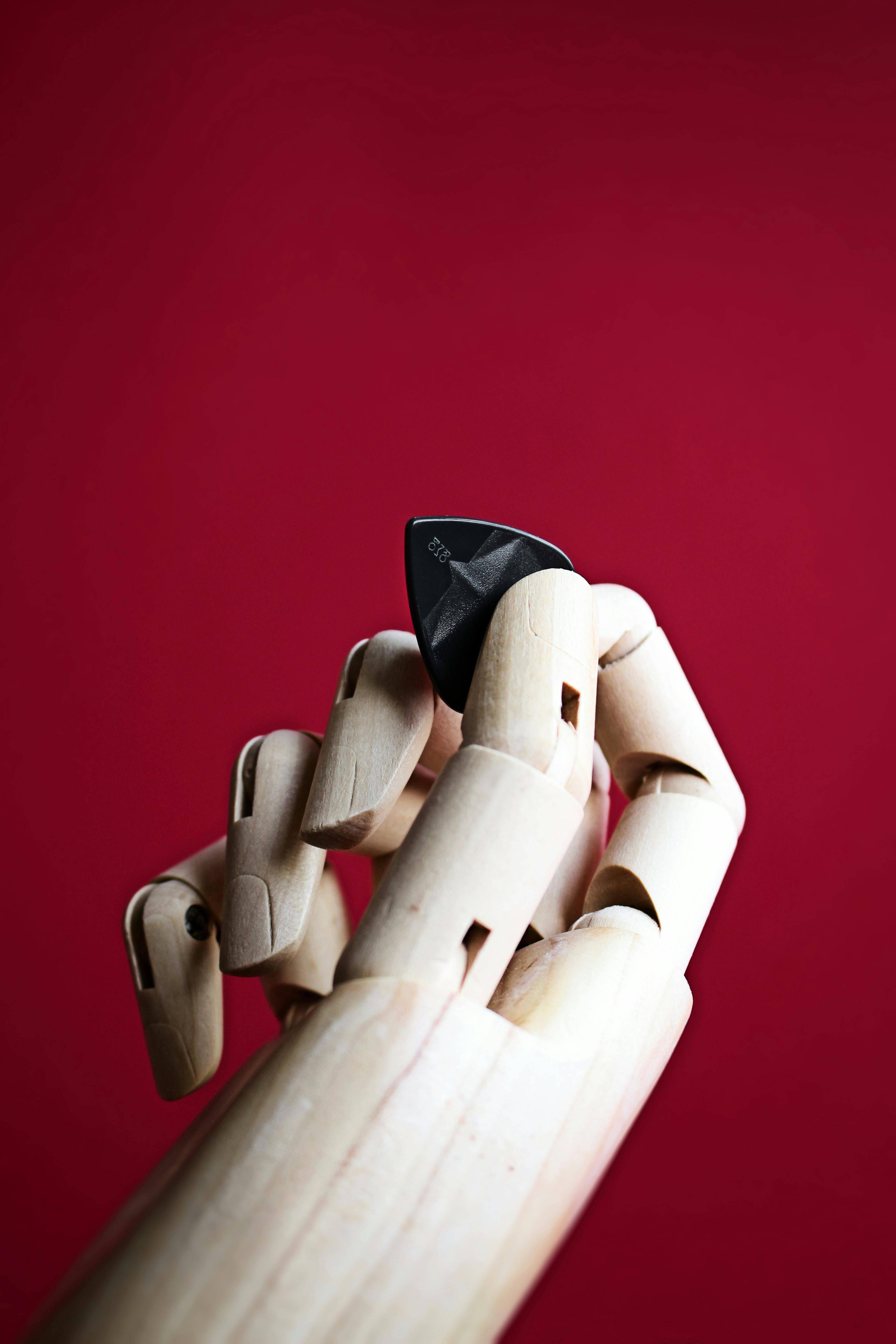 Wooden Prosthetic Hand Holding a Guitar Pick · Free Stock Photo