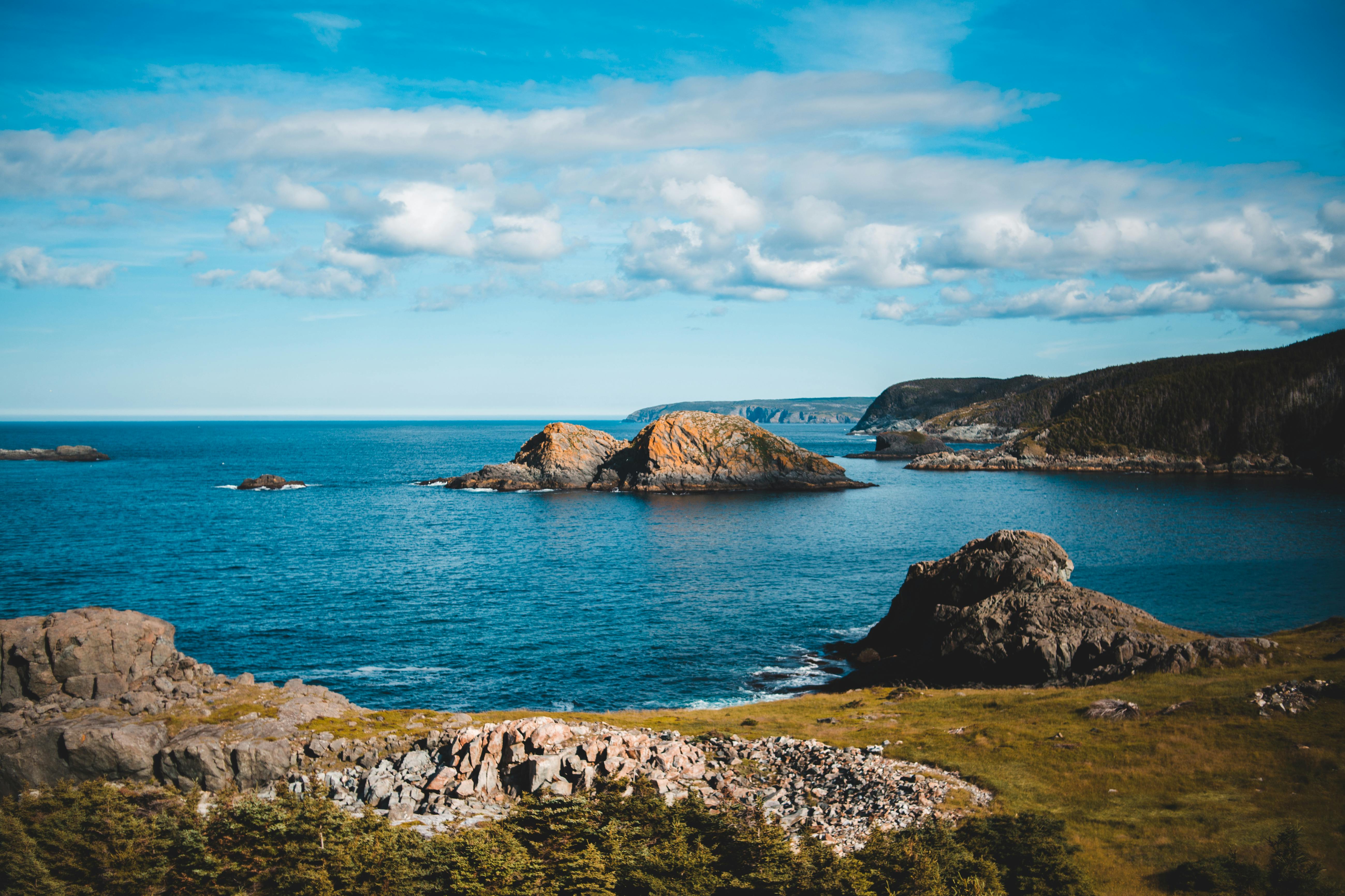 Rocky cliffs in blue sea at daytime · Free Stock Photo