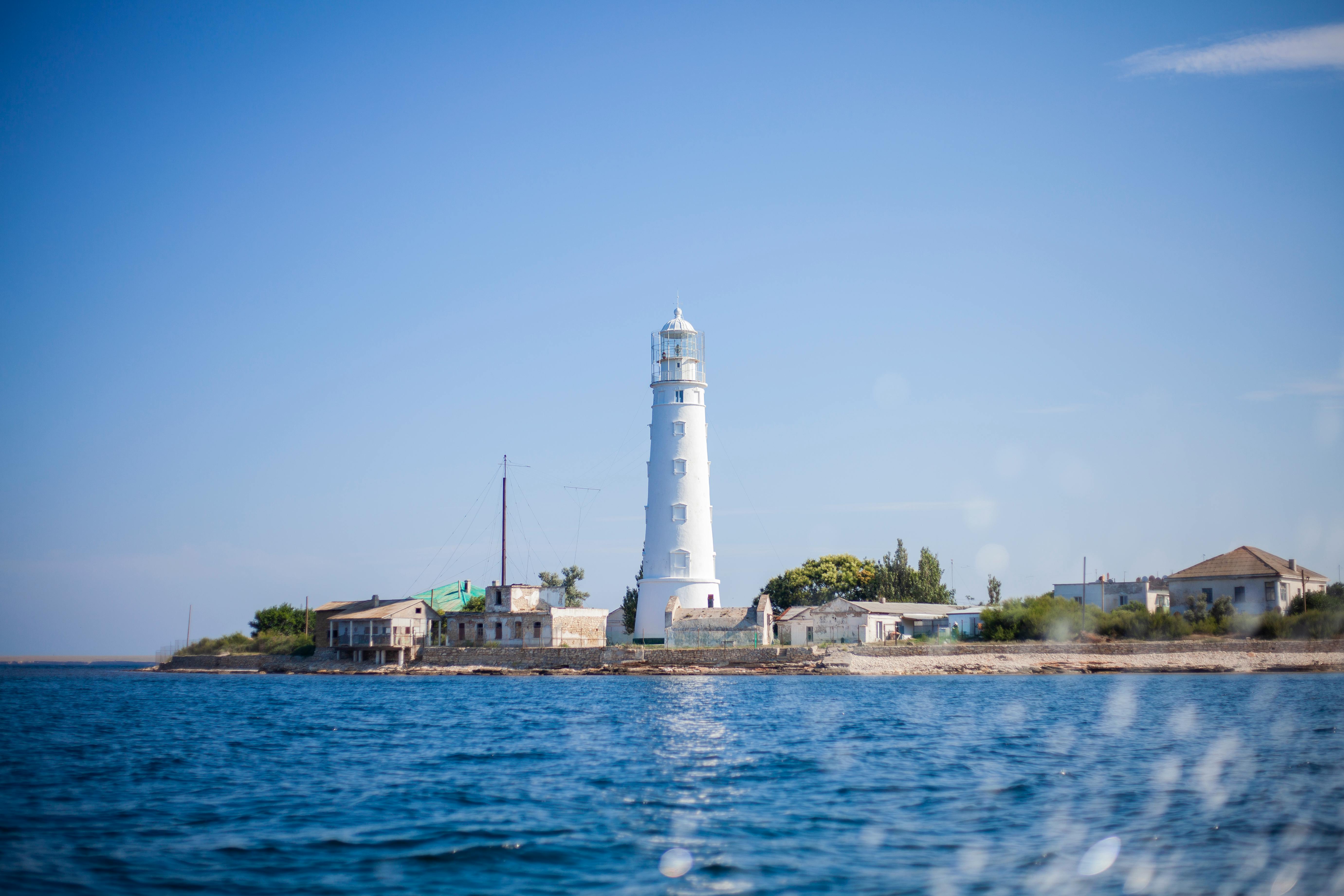 Lone Lighthouse on Shore Overlooking Sea · Free Stock Photo