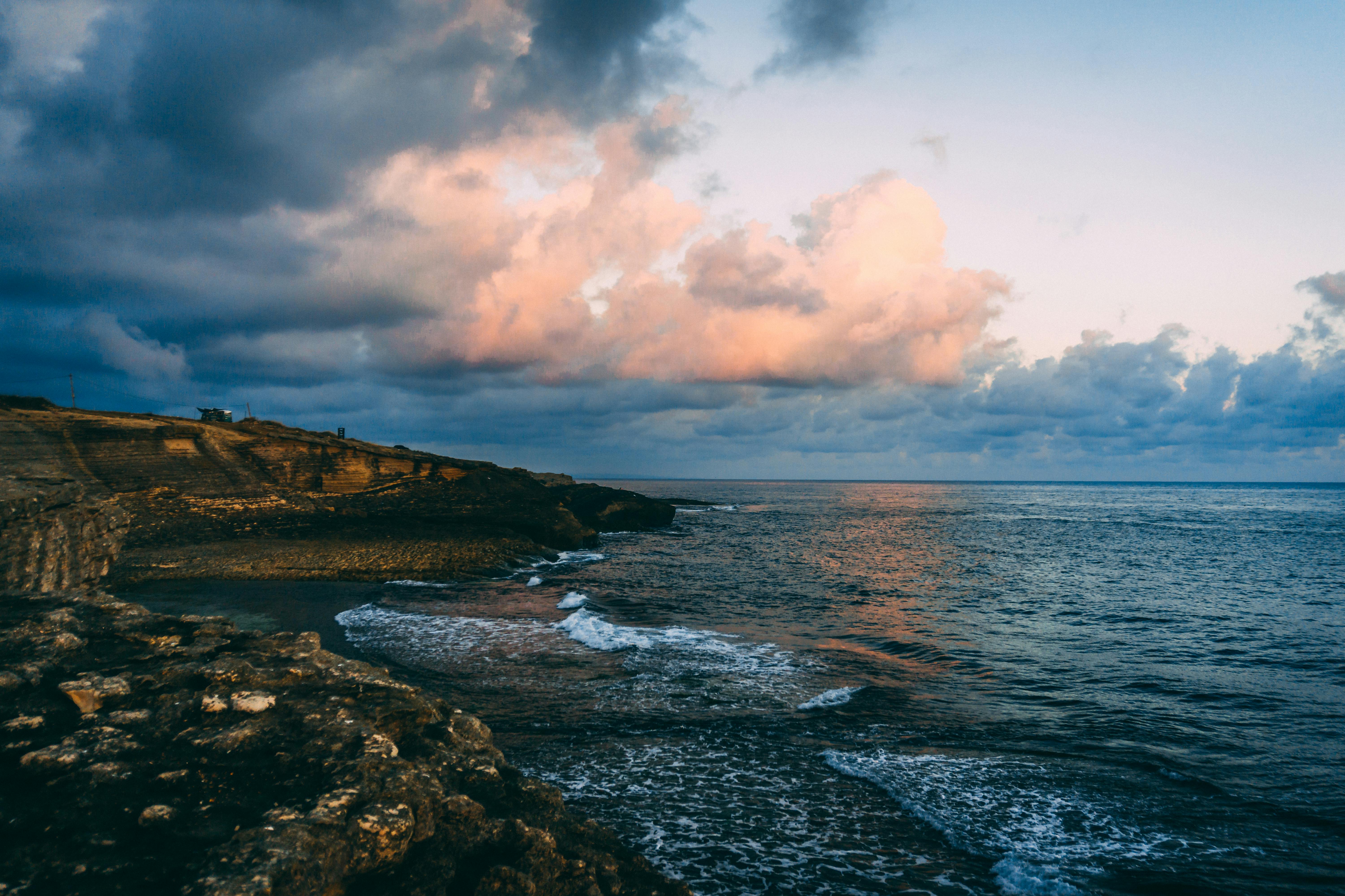 Wavy sea near rocky coast at sunset · Free Stock Photo