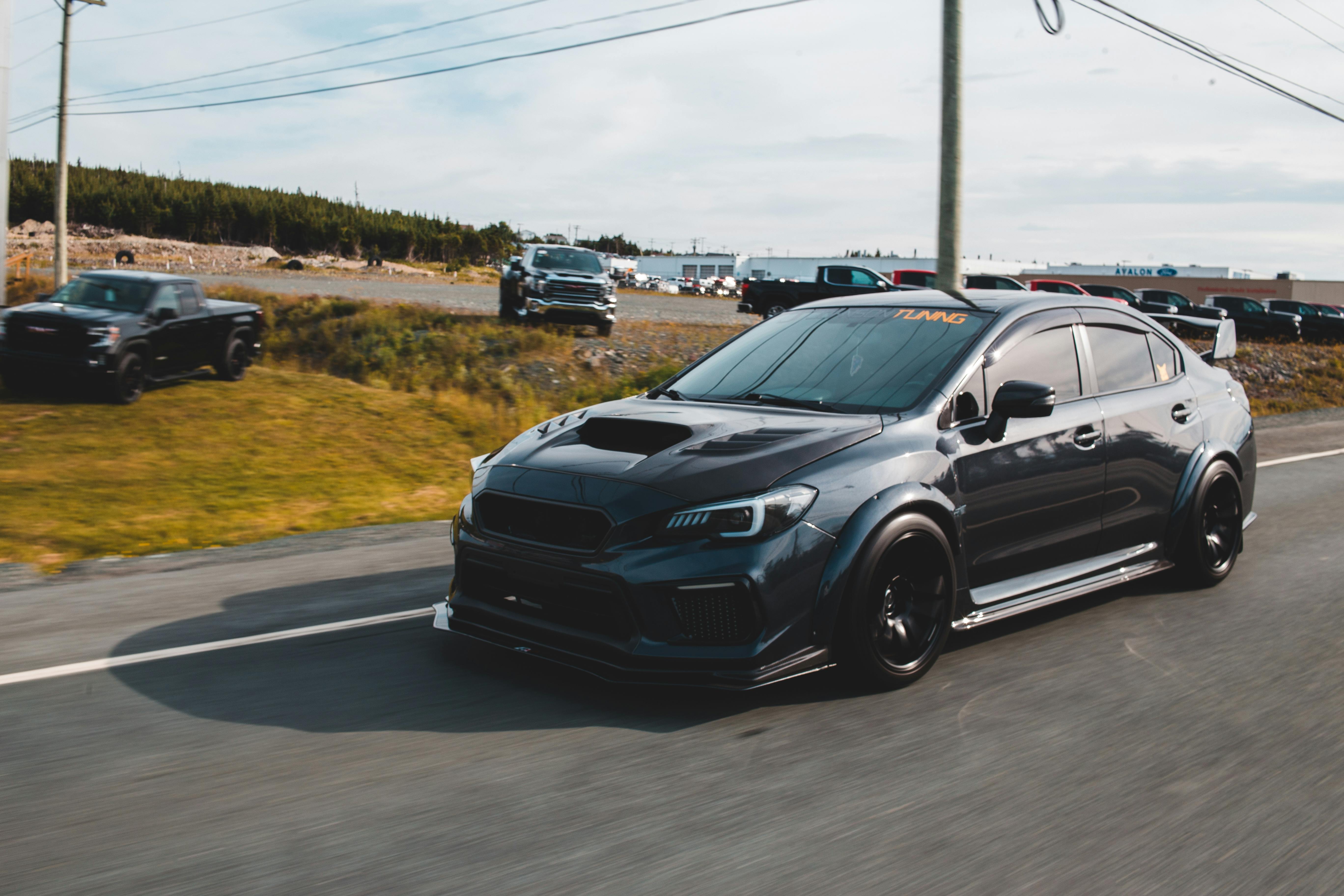 Black car with big body kit riding on paved road · Free Stock Photo