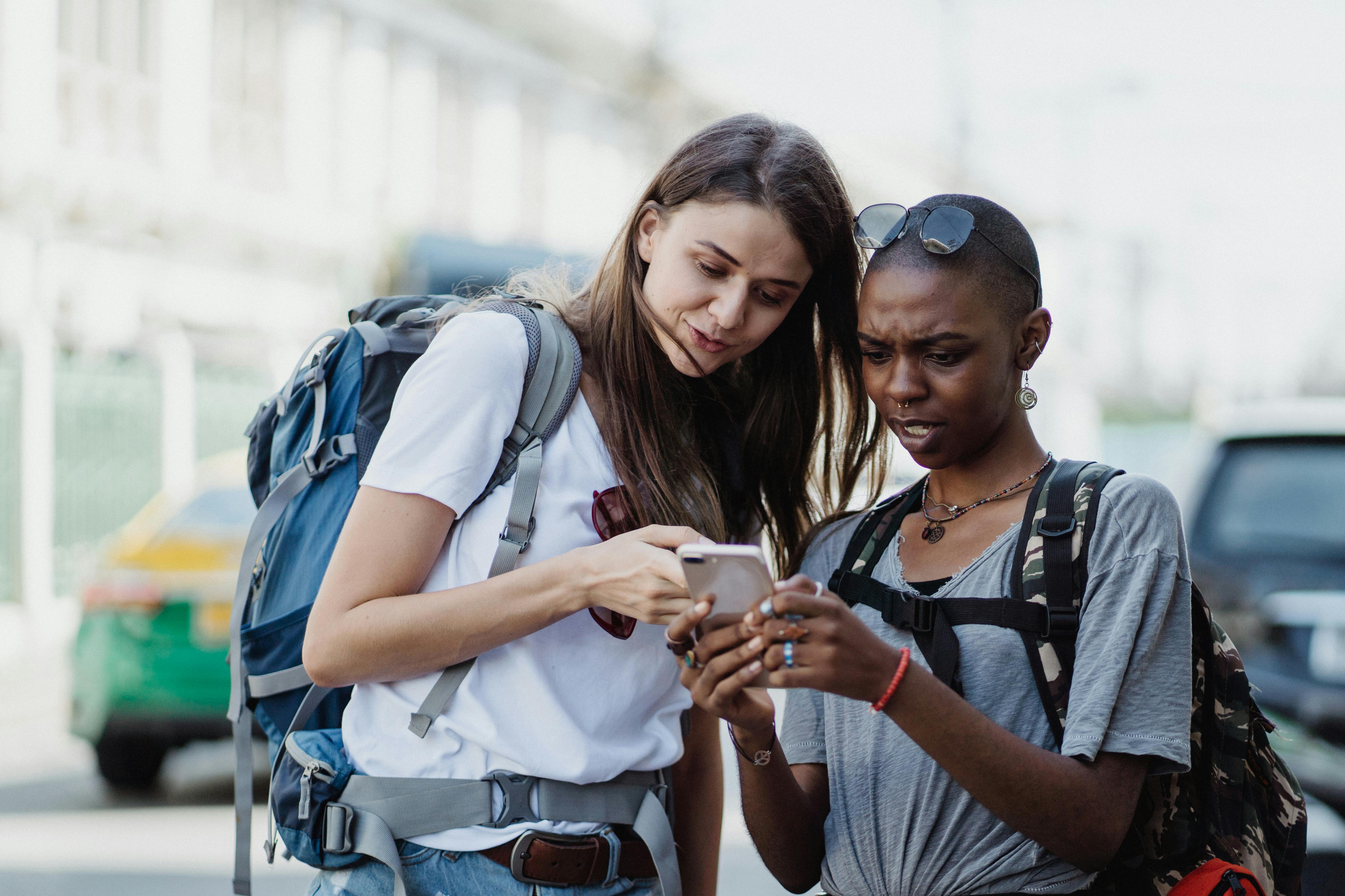 Women with Backpacks Using Phone · Free Stock Photo