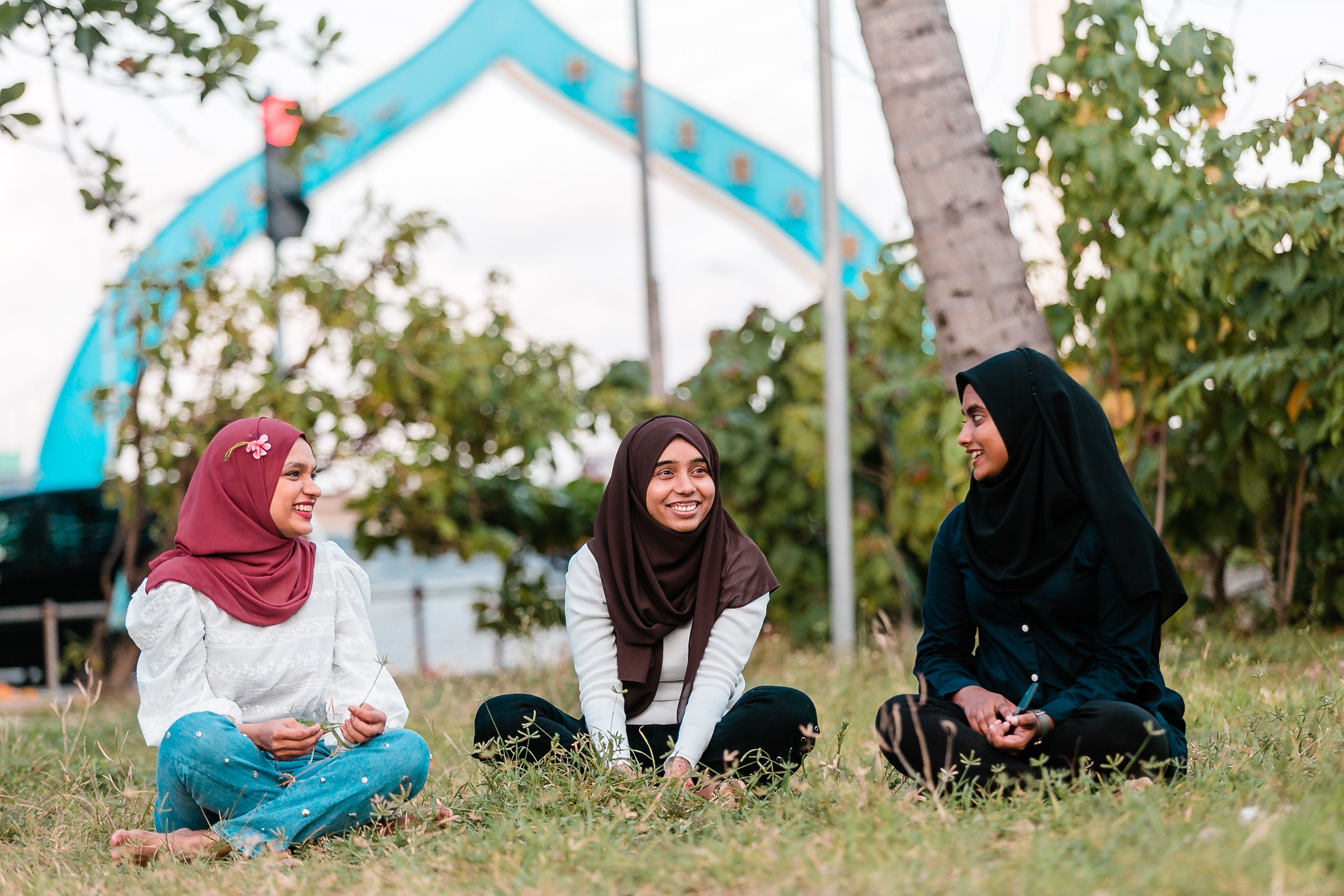 Happy Muslim women chatting and resting on park grass · Free Stock Photo