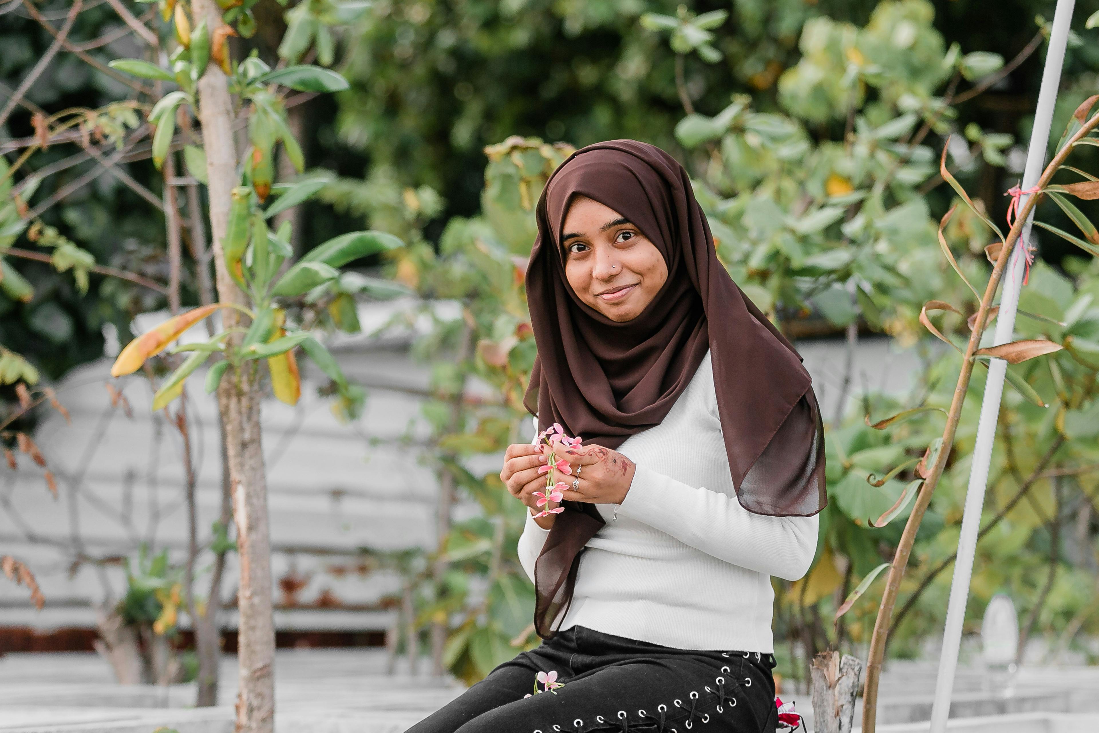 Positive Muslim woman standing in lush park · Free Stock Photo