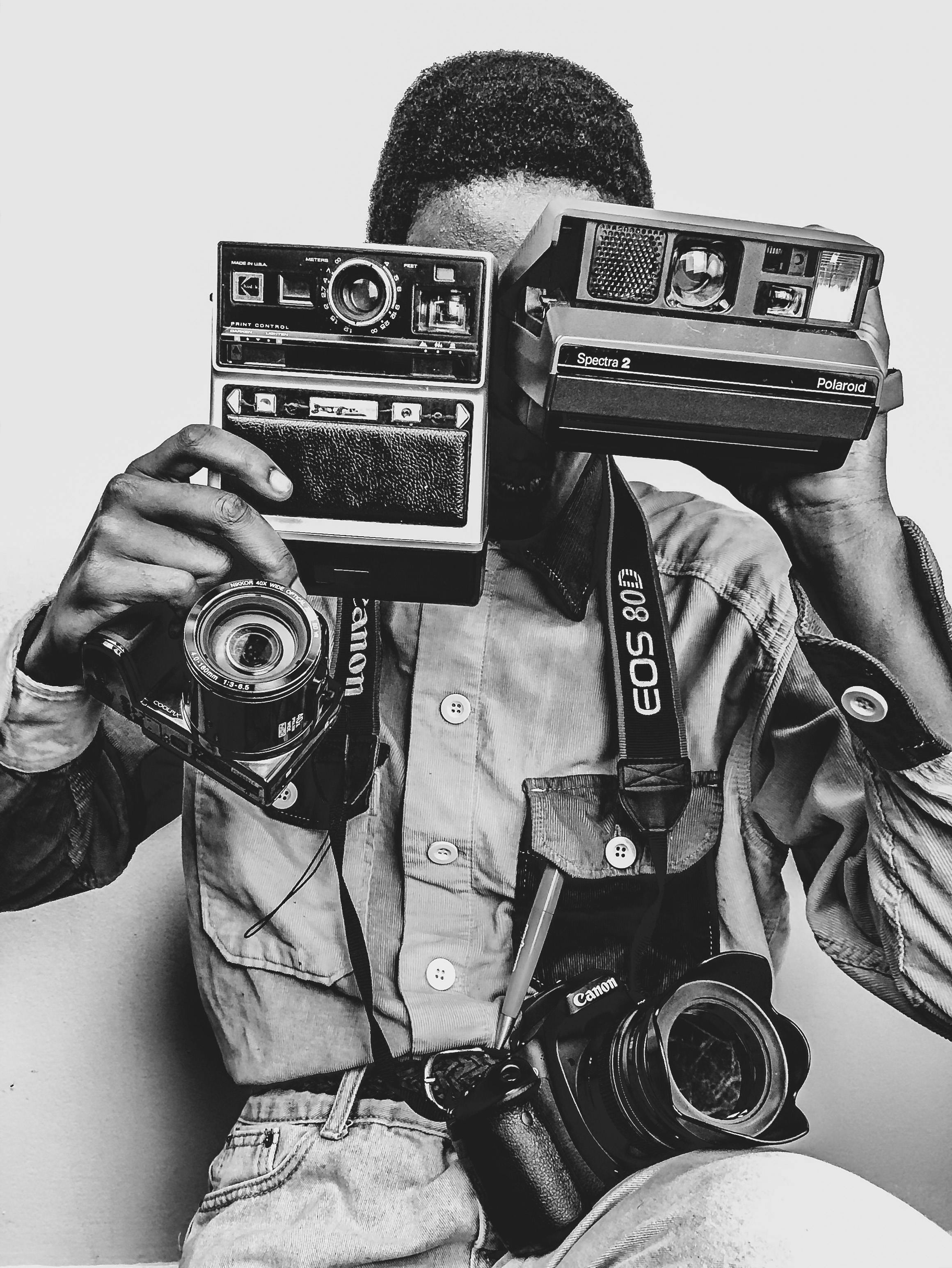 Black and White Photo of a Man Holding Cameras · Free Stock Photo