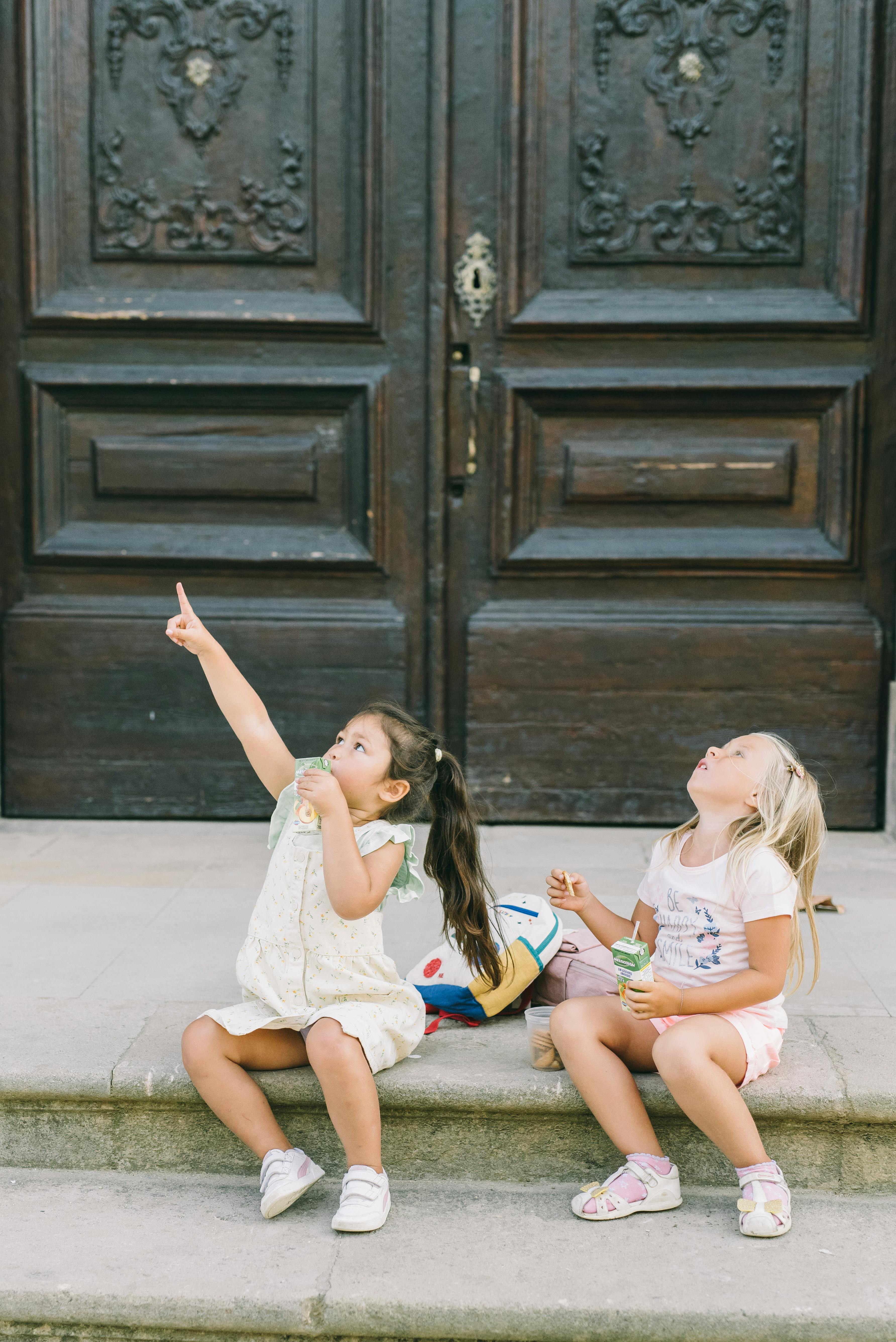 Two kids leaning over puzzle laying on table · Free Stock Photo