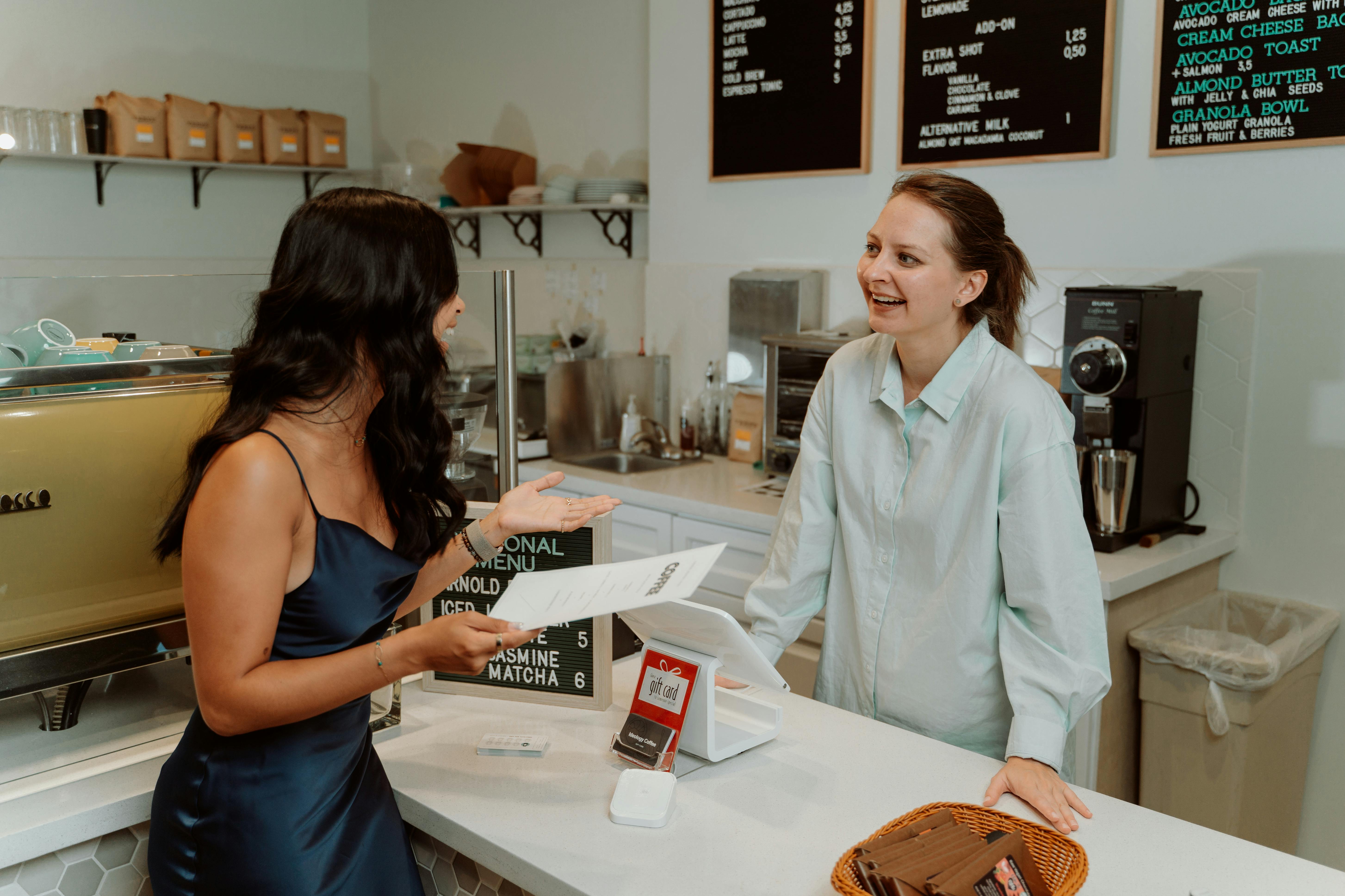 Cheerful black waitress standing at counter · Free Stock Photo