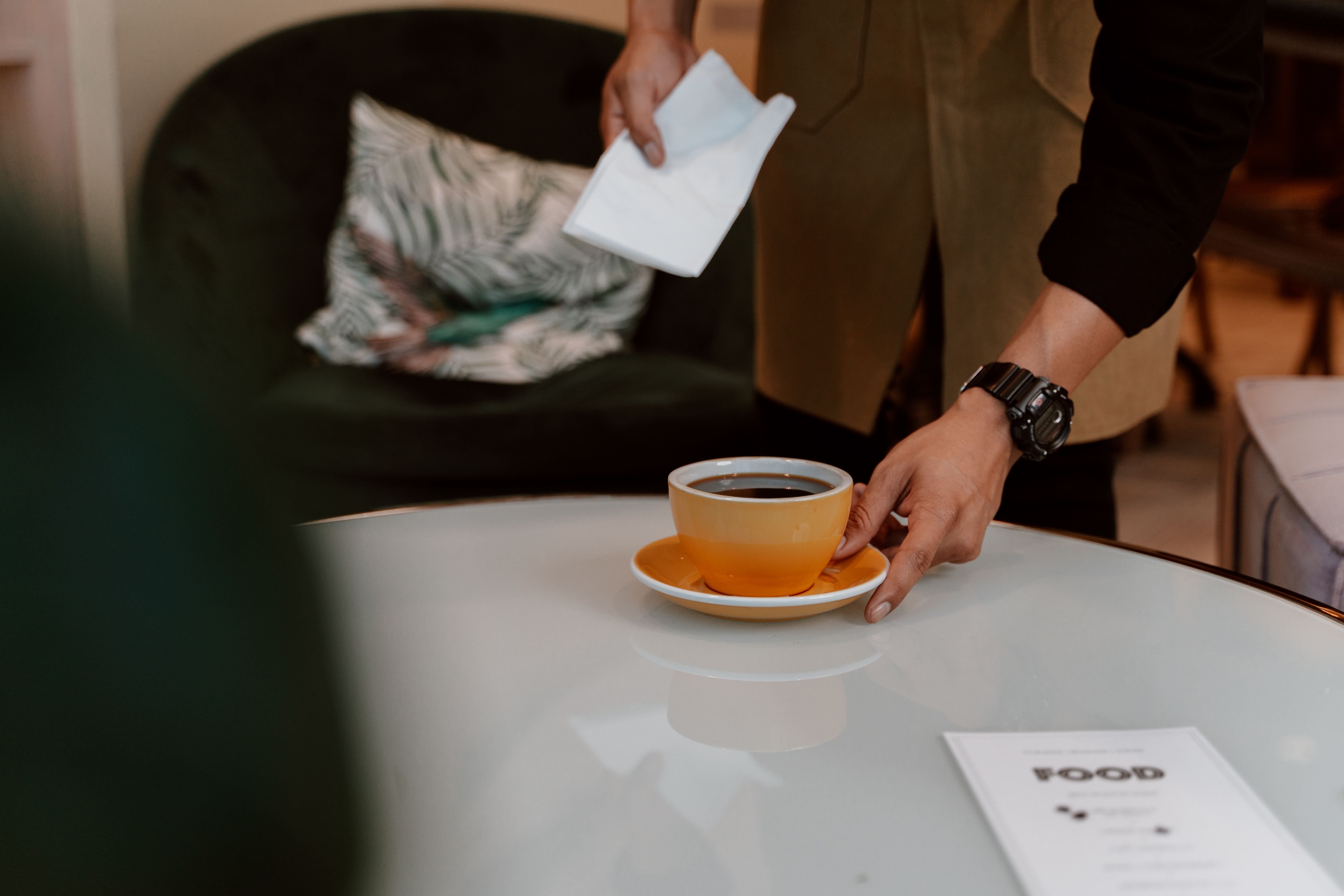 A Person Putting a Cup and Saucer on the Table · Free Stock Photo