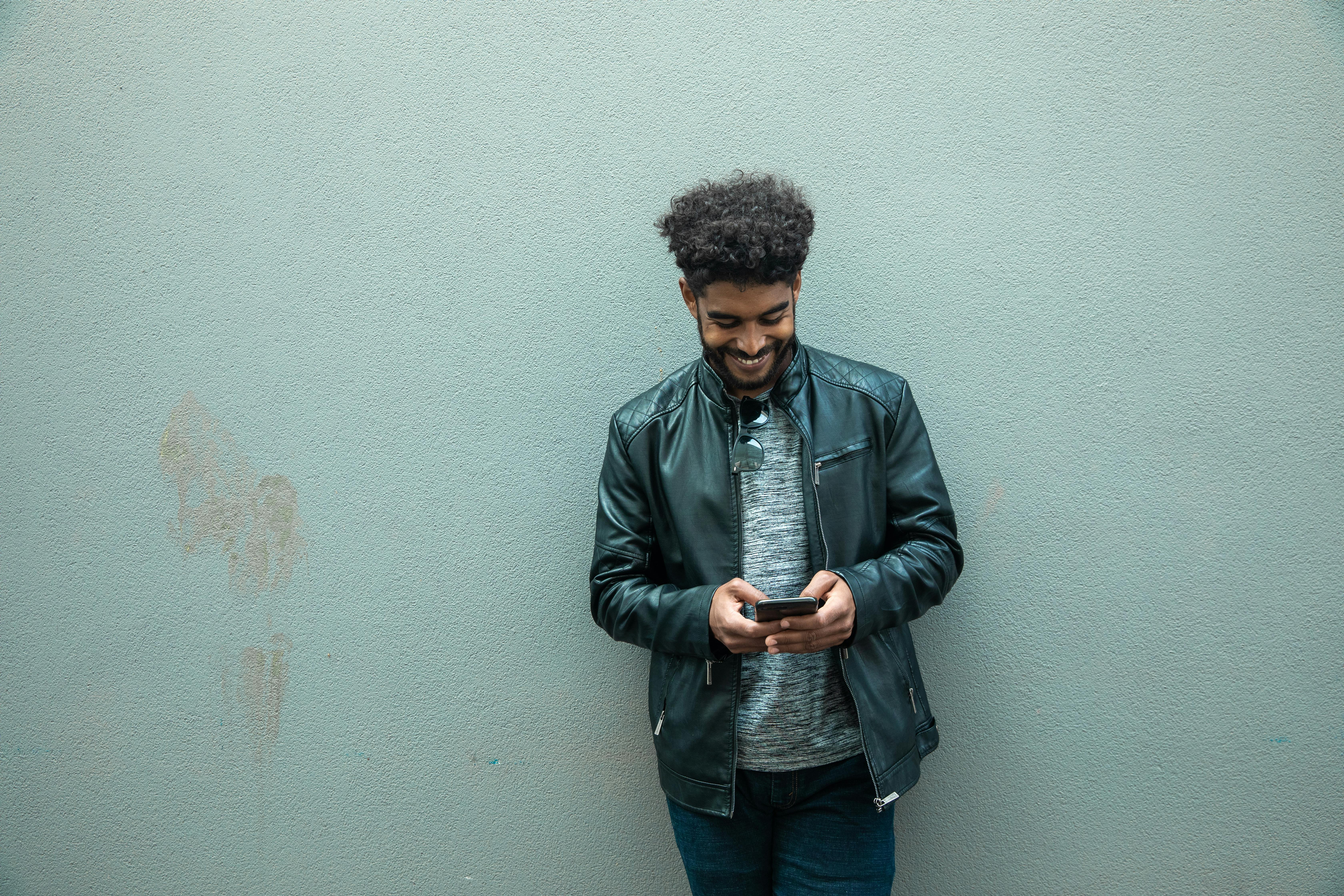 A Man Smiling While Texting · Free Stock Photo