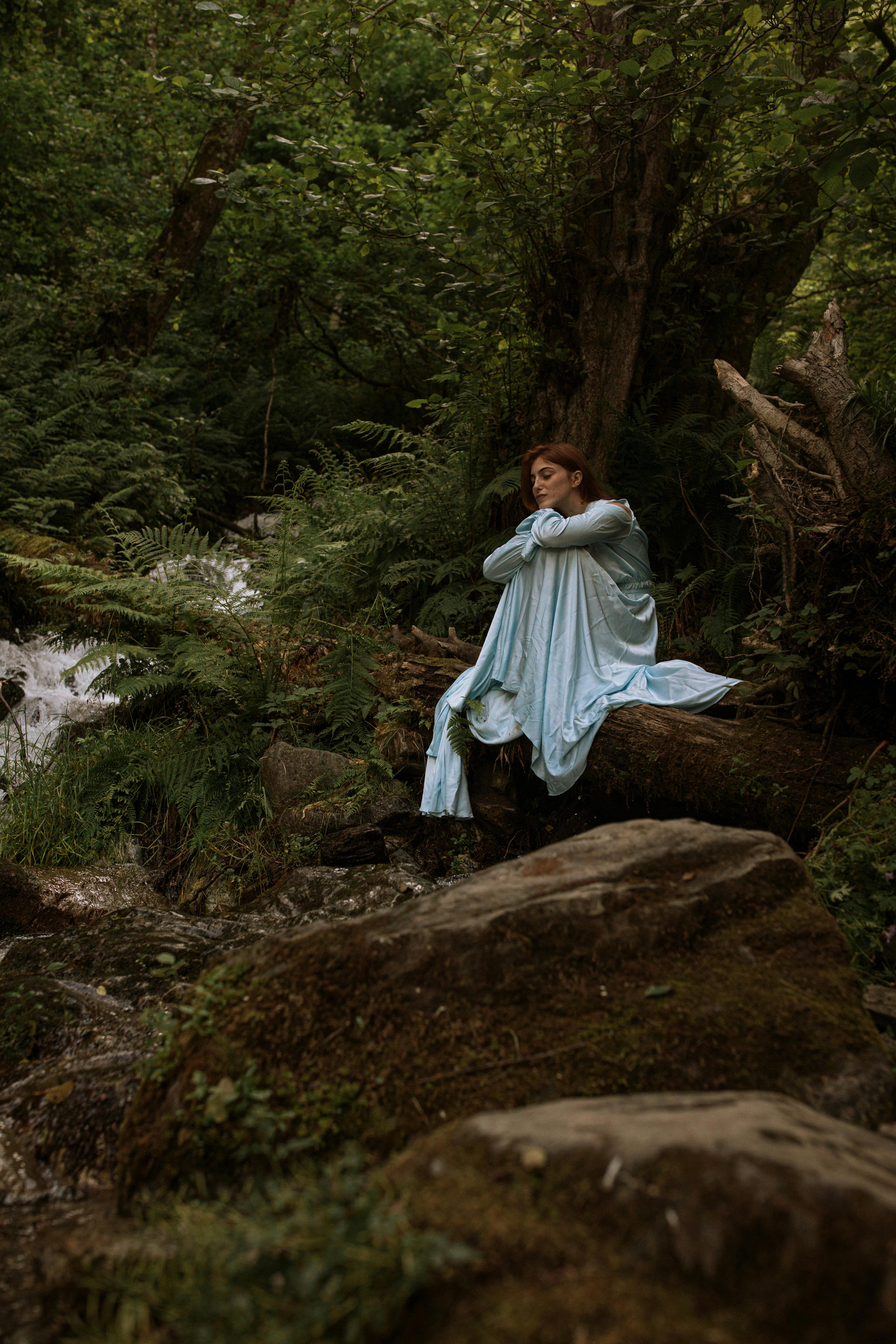 Woman in a Blue Dress Sitting in the Middle of a Forest · Free Stock Photo