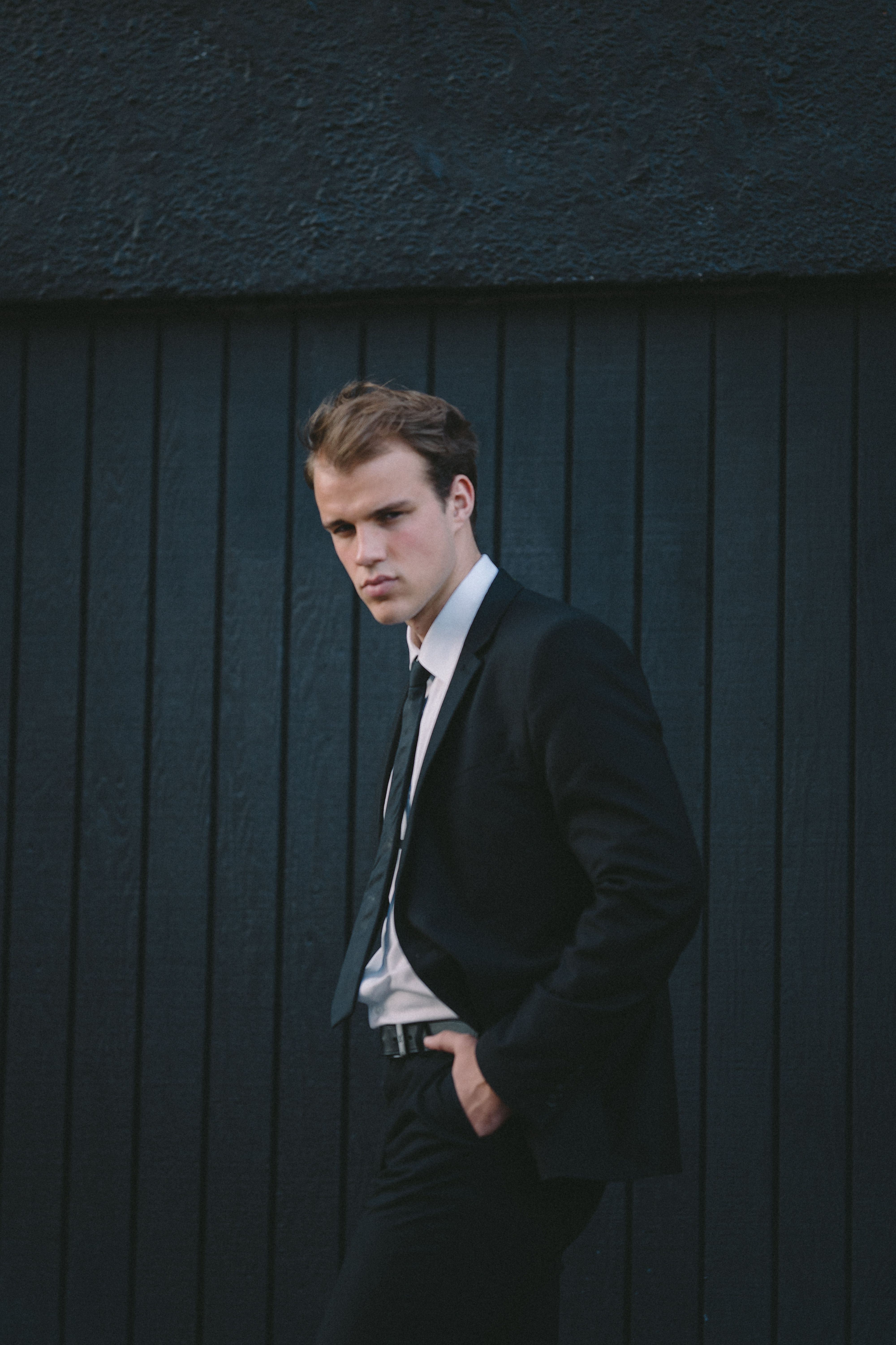 Young man standing near wooden wall · Free Stock Photo