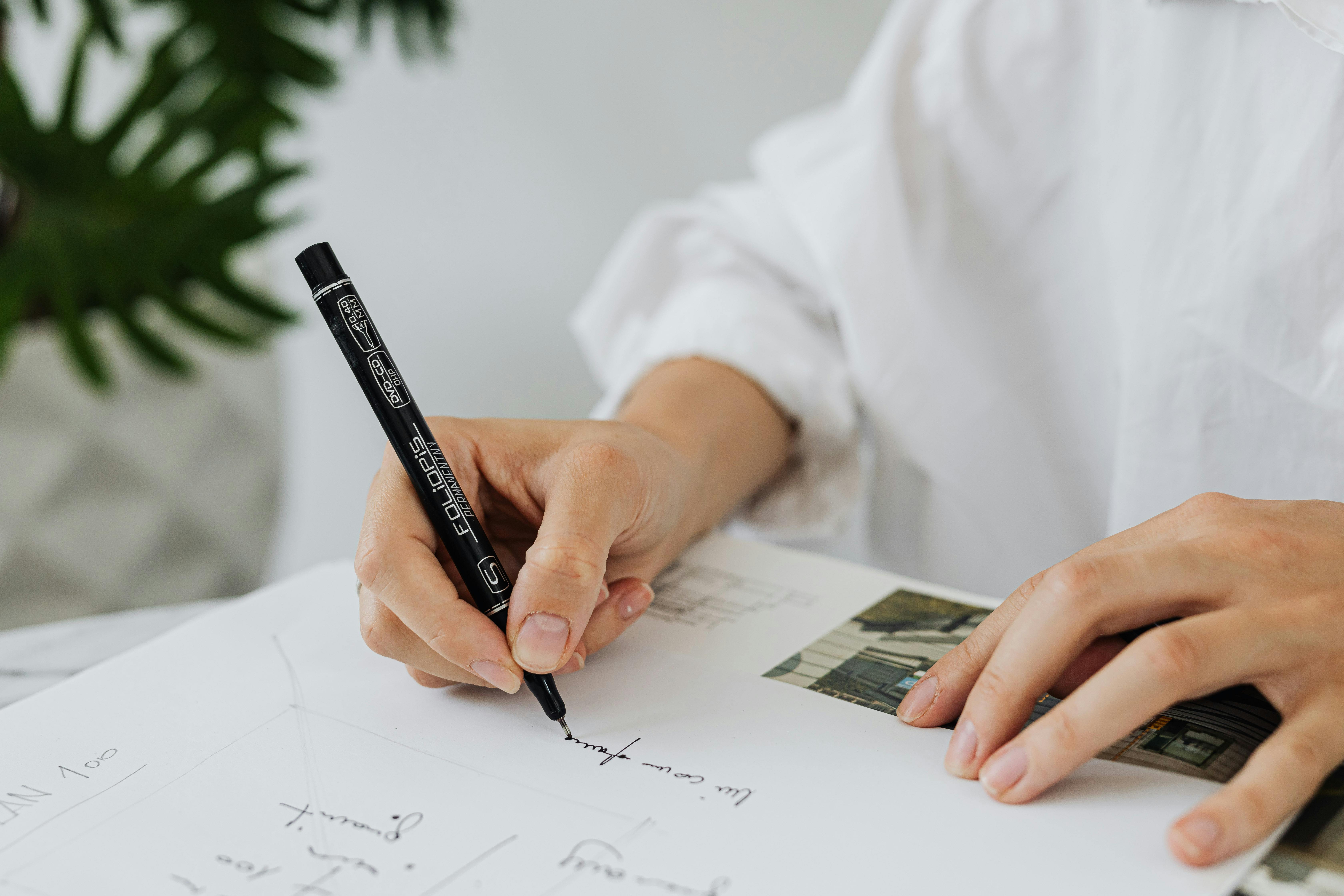 A Person Writing on White Paper · Free Stock Photo
