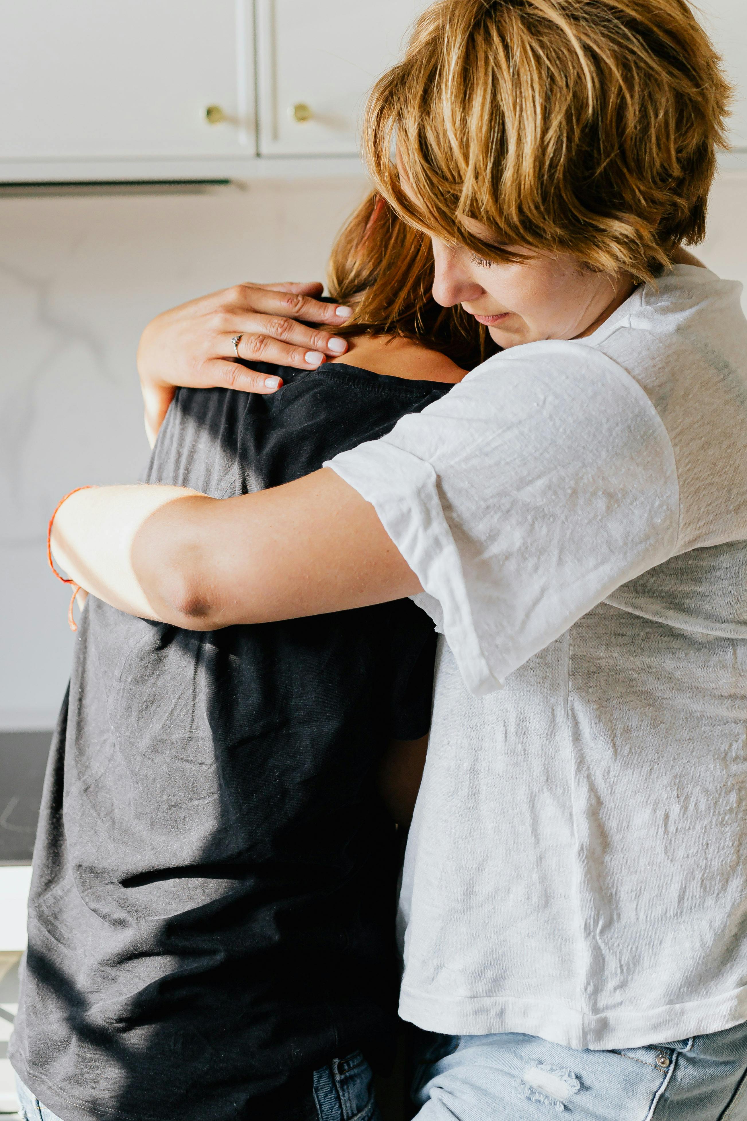 Women Hugging Near Kitchen Cabinets · Free Stock Photo
