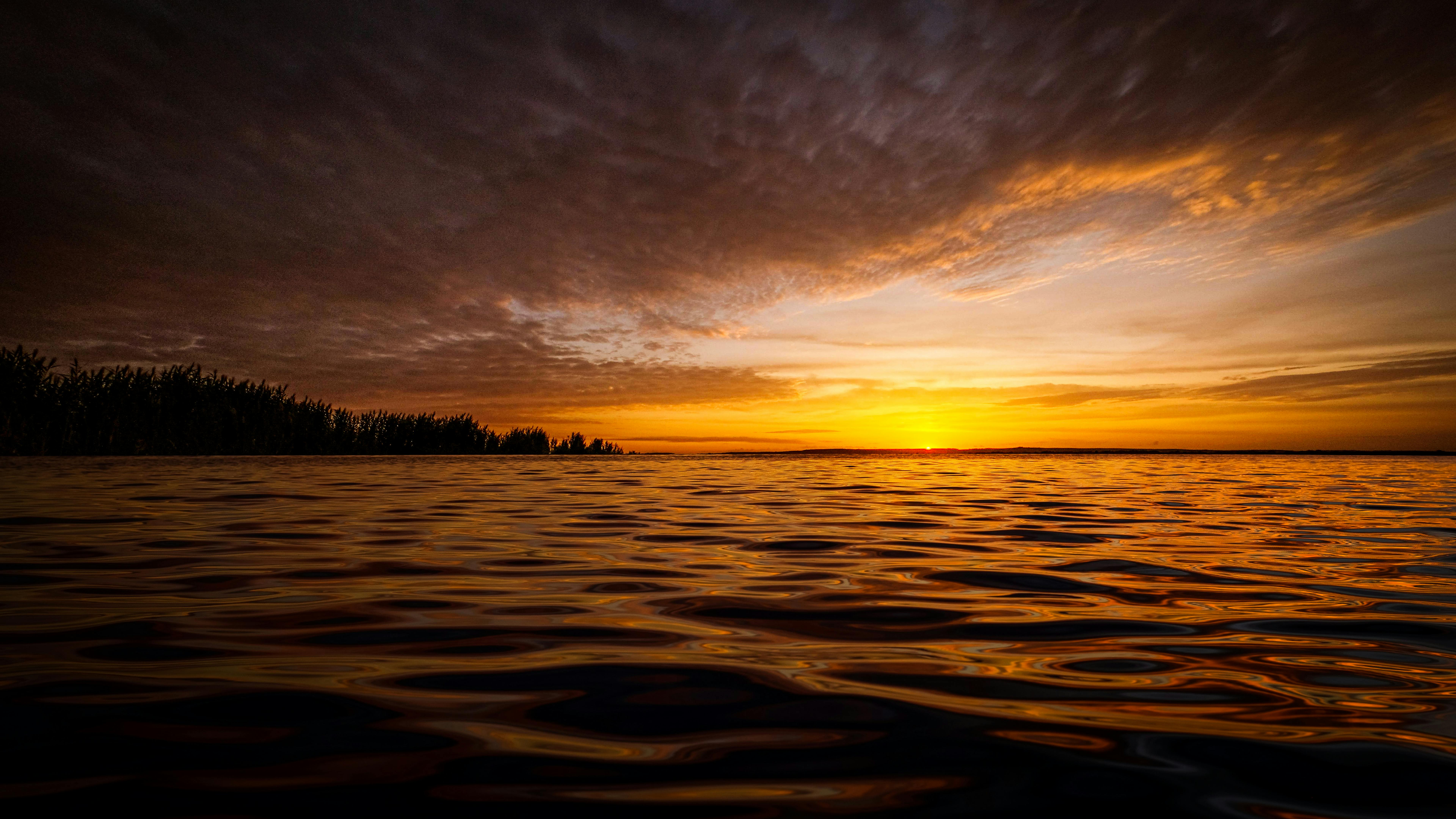 Photograph of a Body of Water Under a Cloudy Sky During Sunset · Free ...