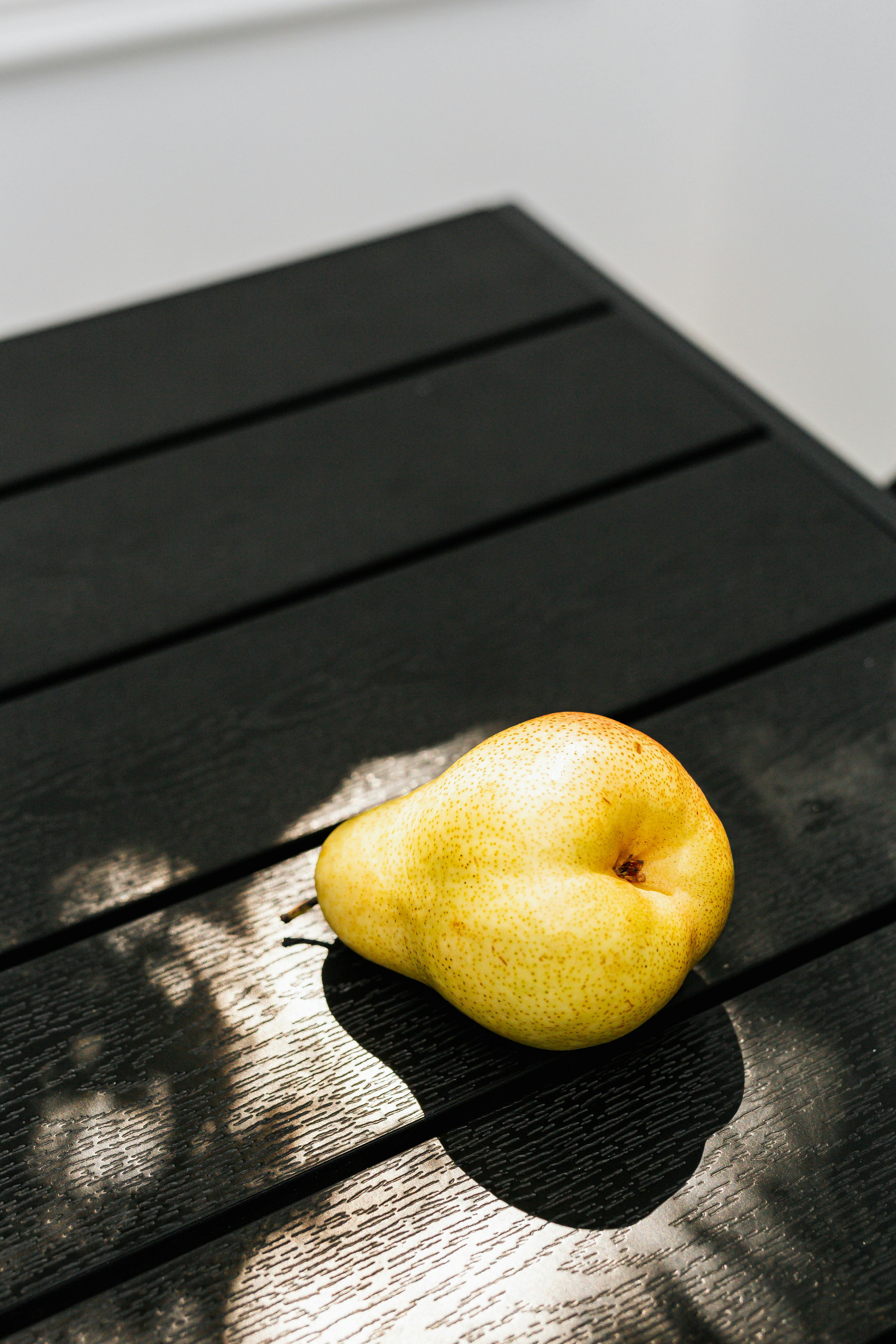 Pear Casting Shadow on Wooden Table · Free Stock Photo