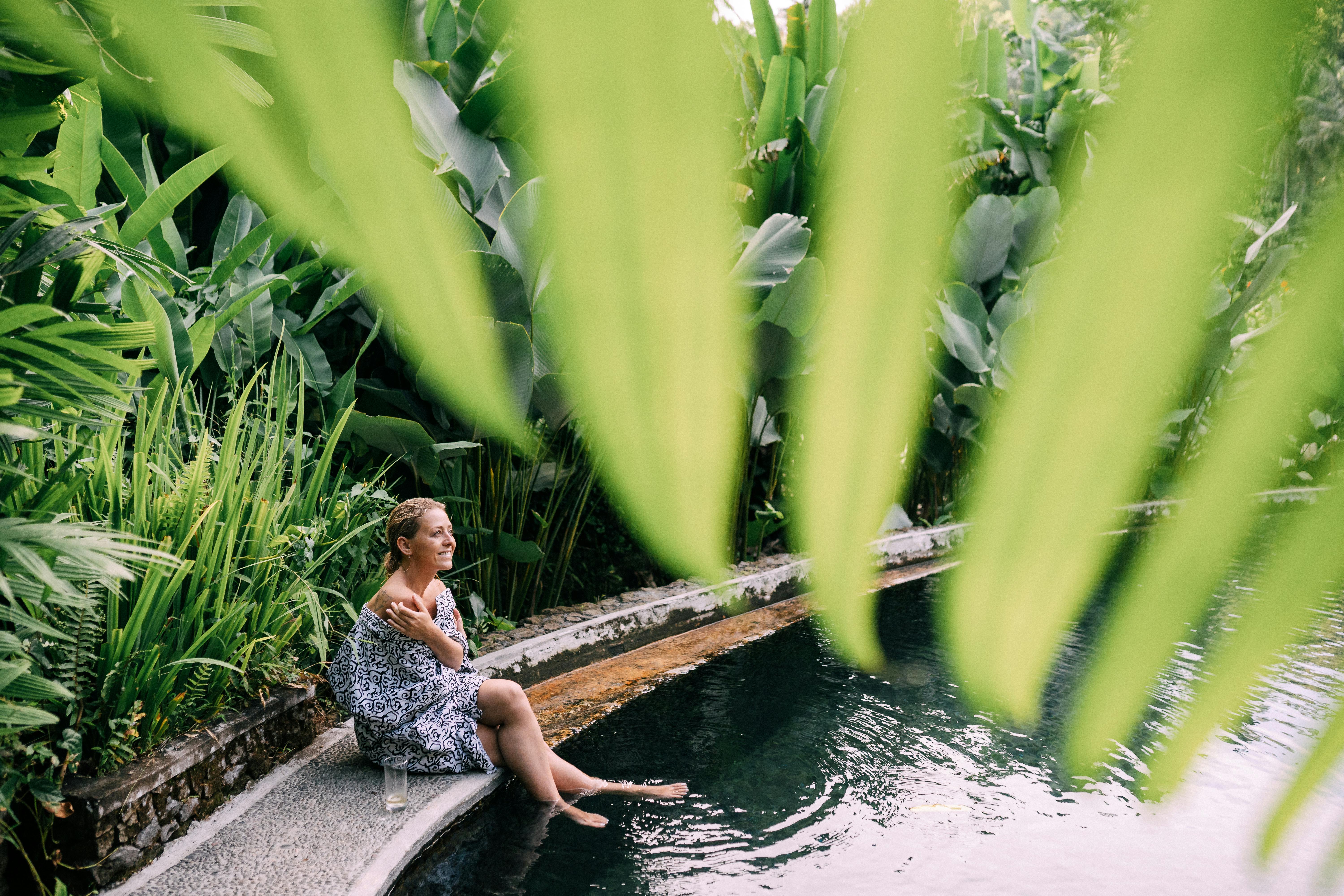 Woman Sitting with Her Feet in Water in a Tropical Pool Among Plants ...