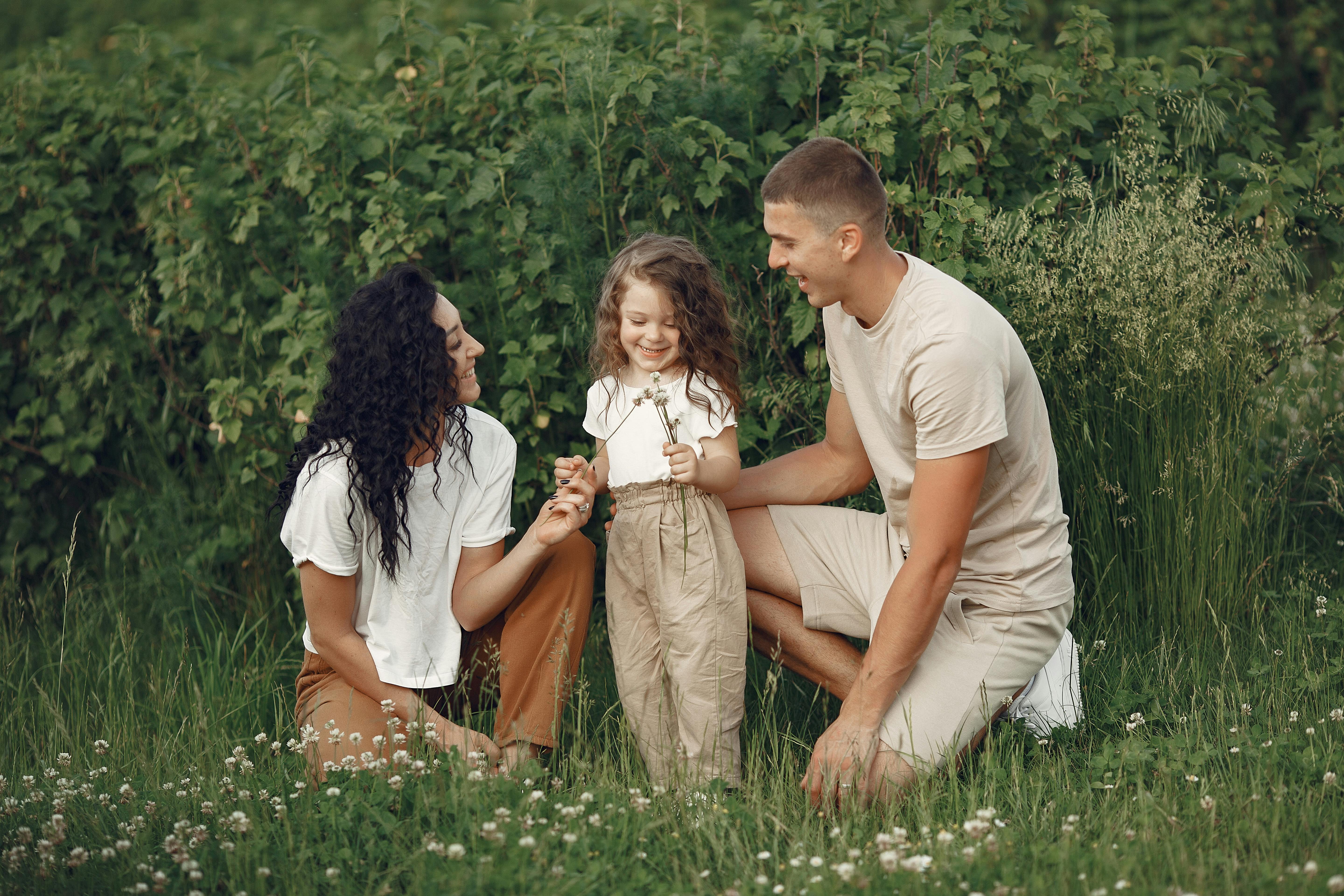 Family on Field Picking up Flowers · Free Stock Photo