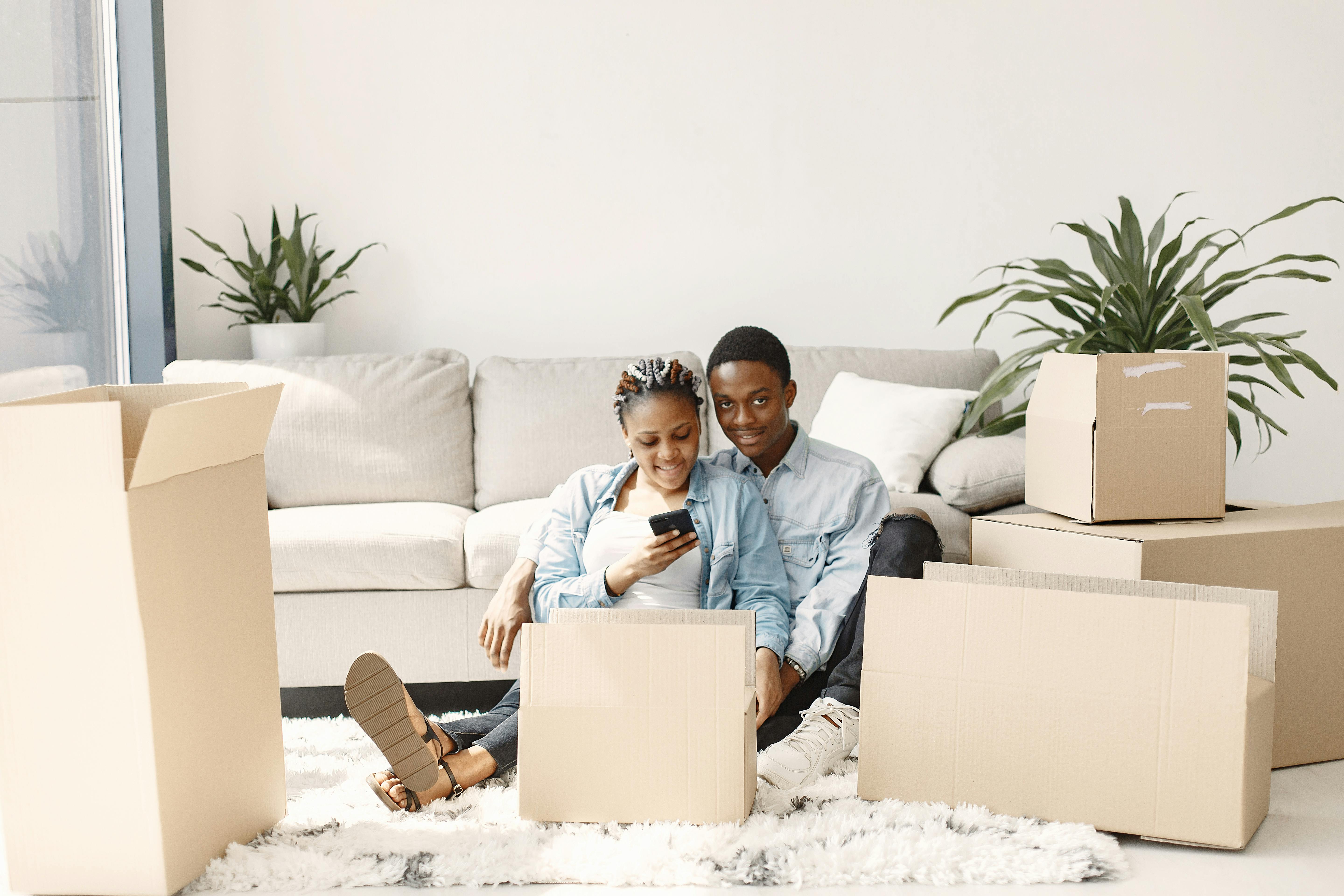 A Young Couple Sitting in a Living Room Full of Cardboard Boxes · Free ...
