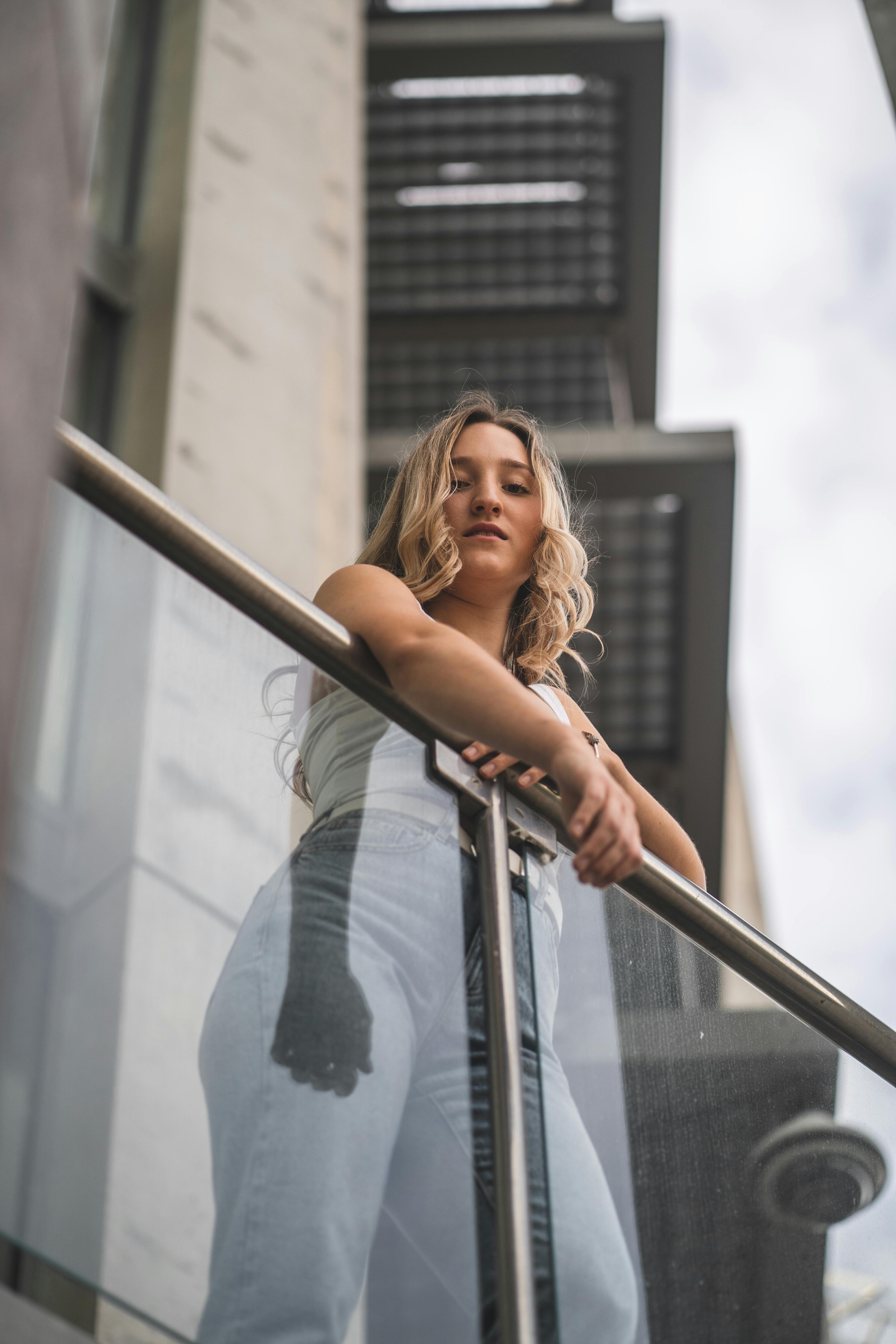 Portrait of Person in Purple Jacket Leaning Against Glass Railing ...