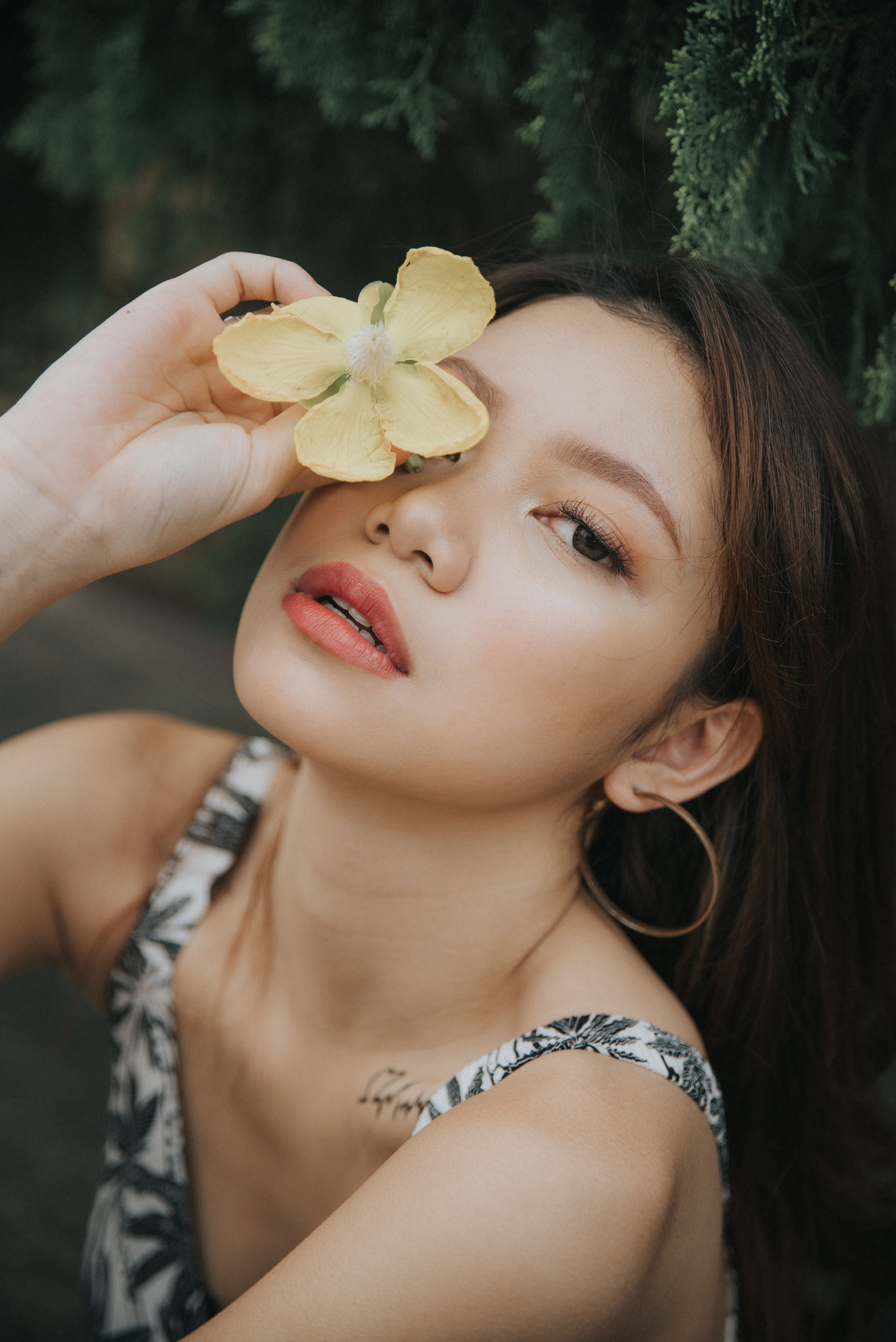 Trendy Asian woman covering eye with flower · Free Stock Photo
