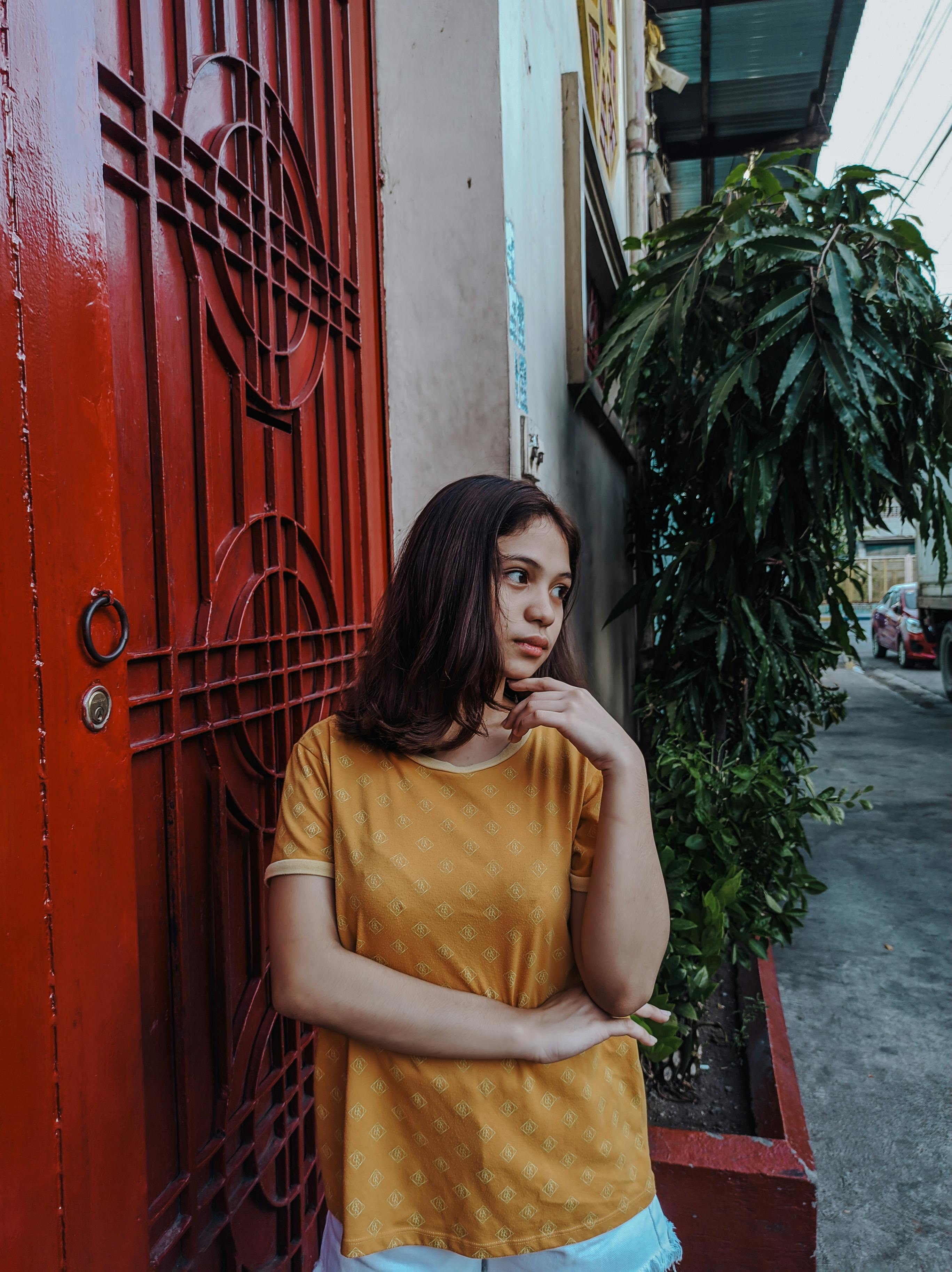 Dreamy woman touching chin on town street · Free Stock Photo