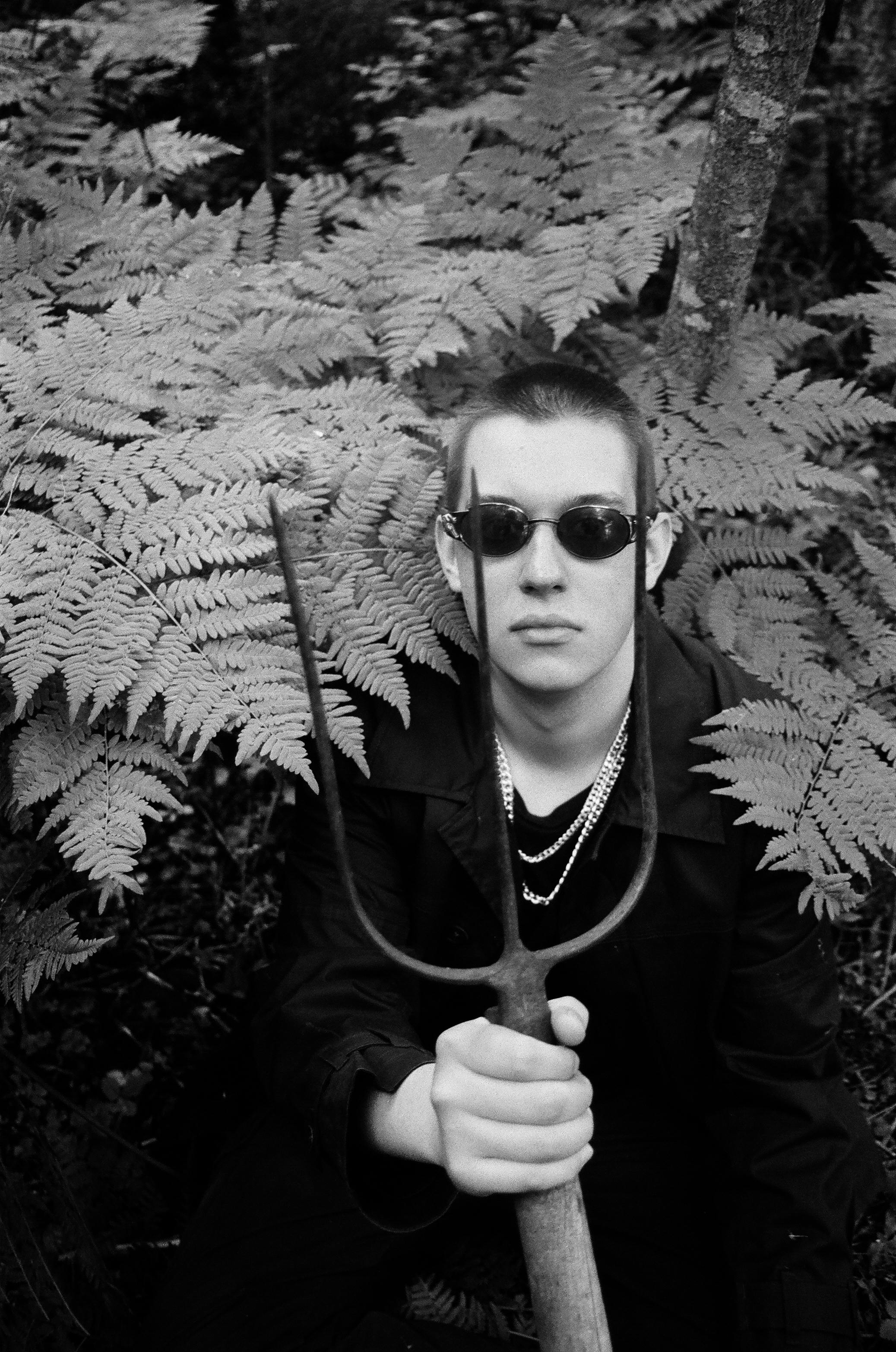 Informal man with pitchfork against fern · Free Stock Photo