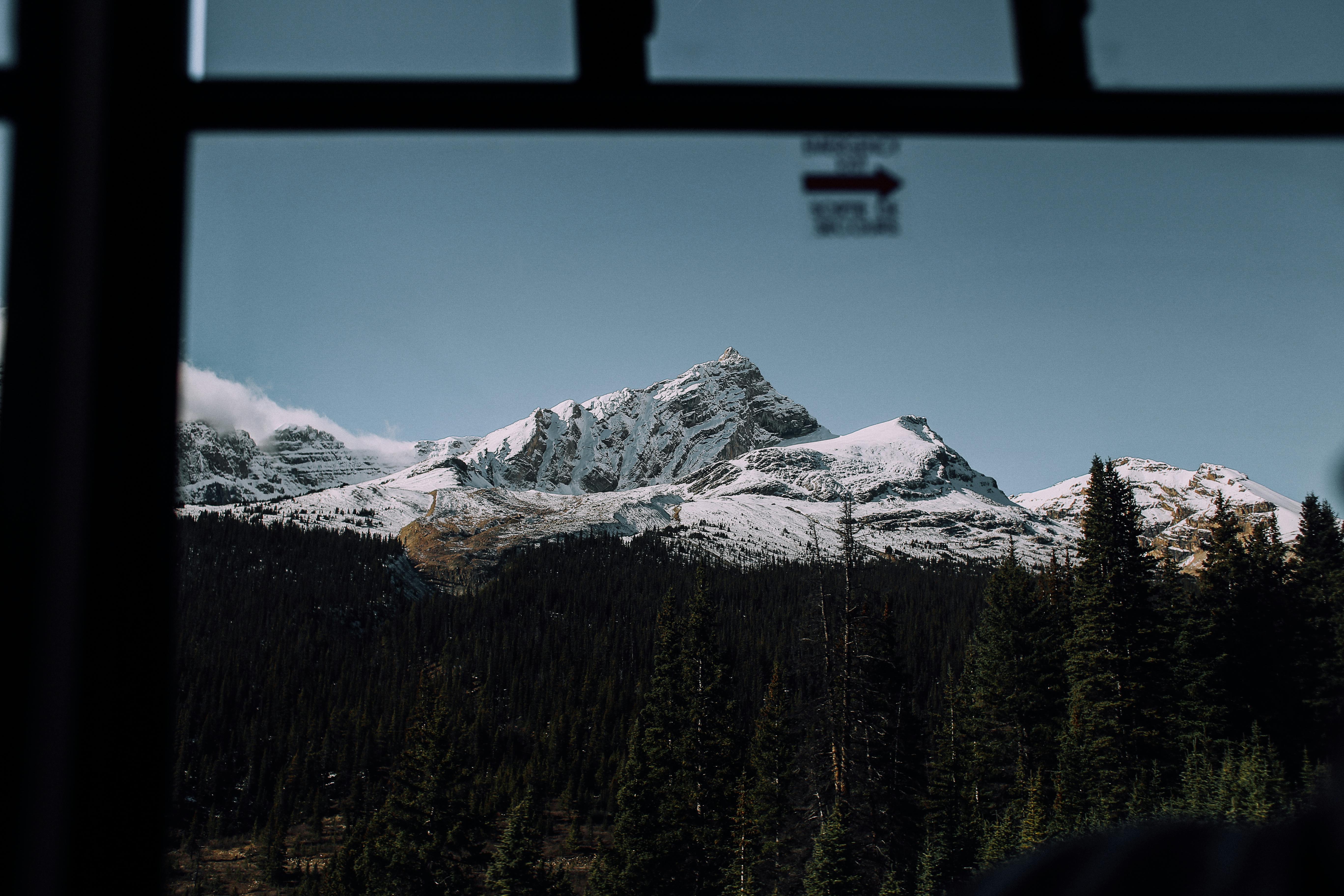 Through window view of snowy mountains near forest in daylight · Free ...