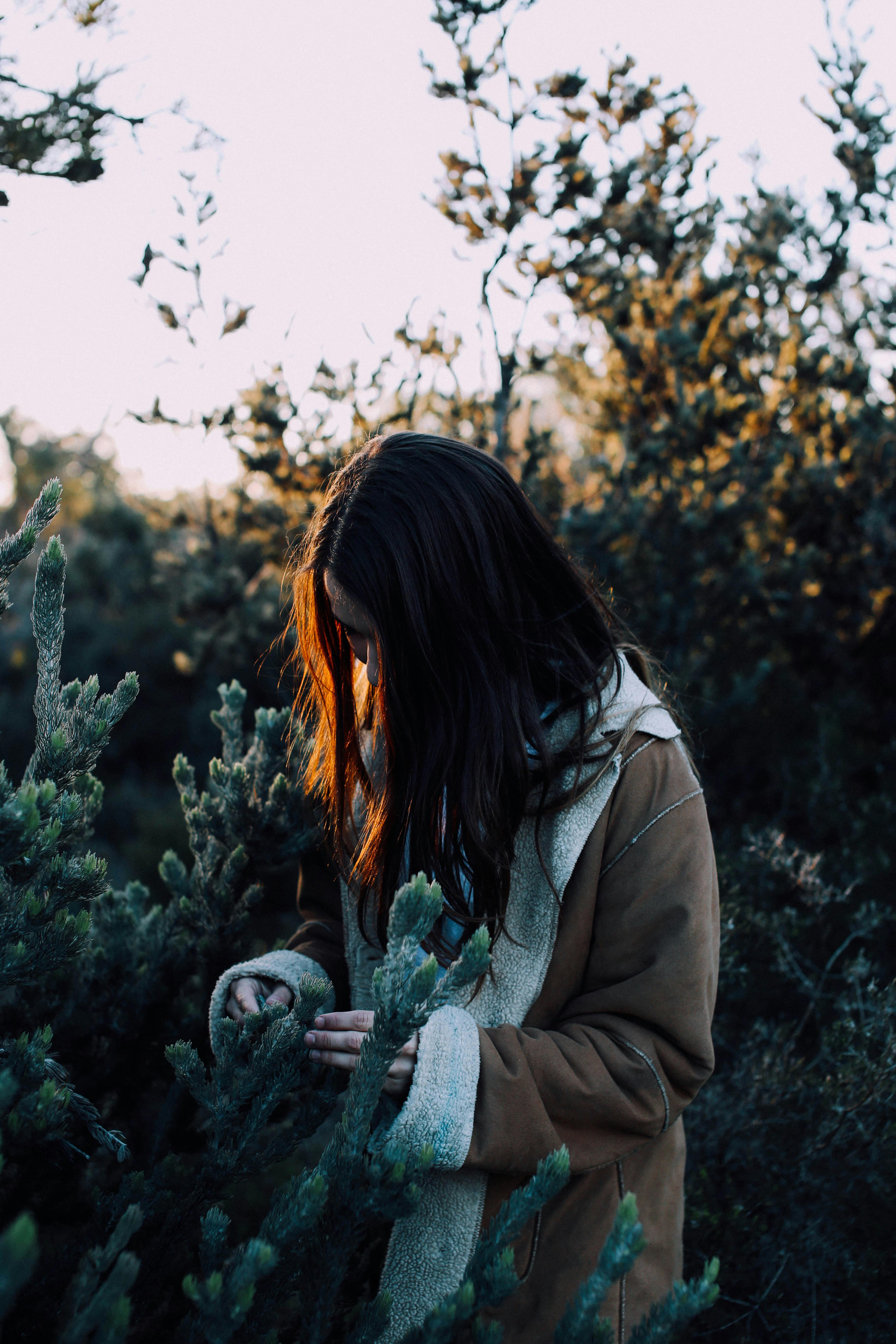 Anonymous woman standing amidst green shrubs · Free Stock Photo