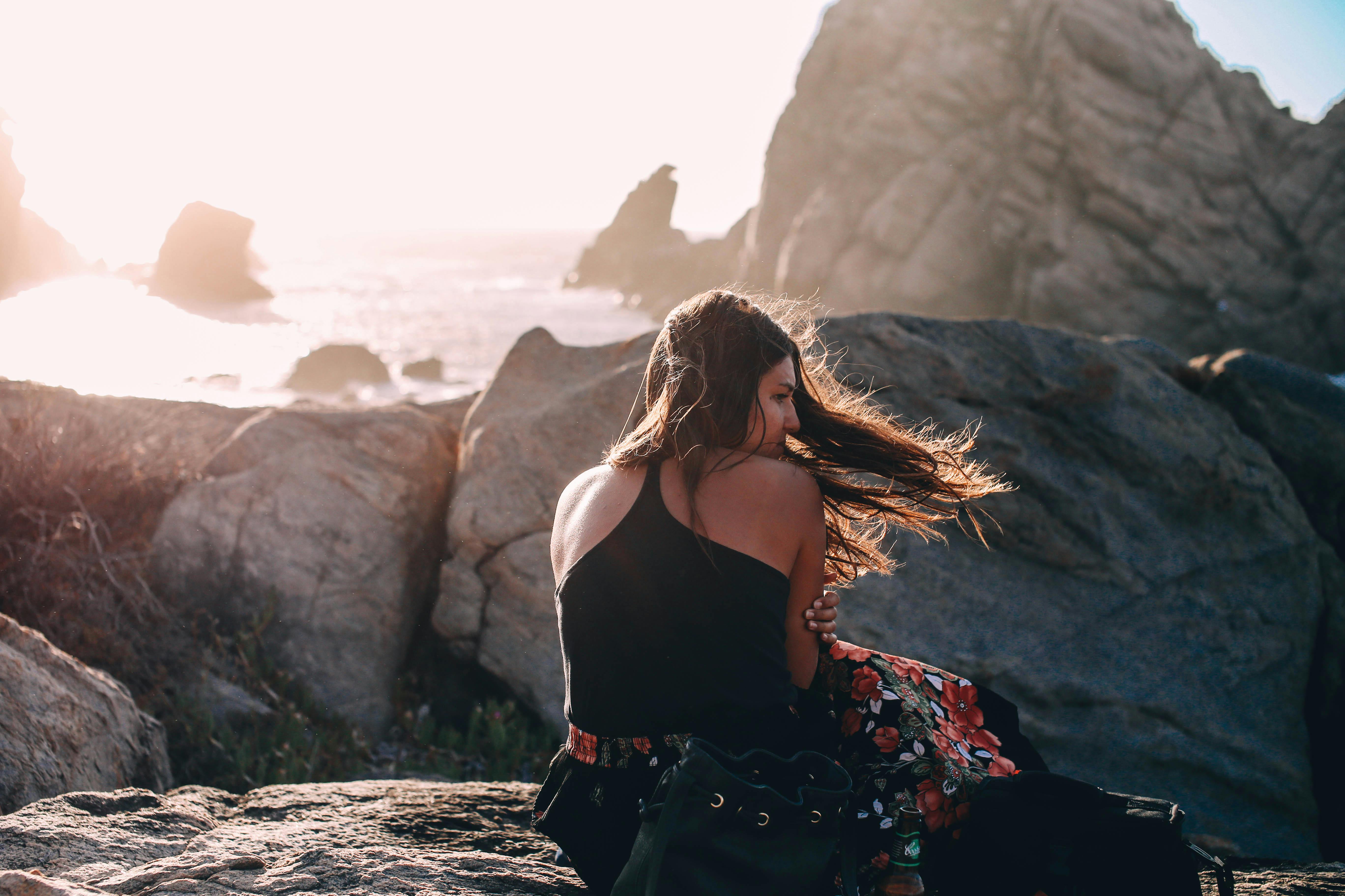 Calm woman on rocky seashore on windy day · Free Stock Photo