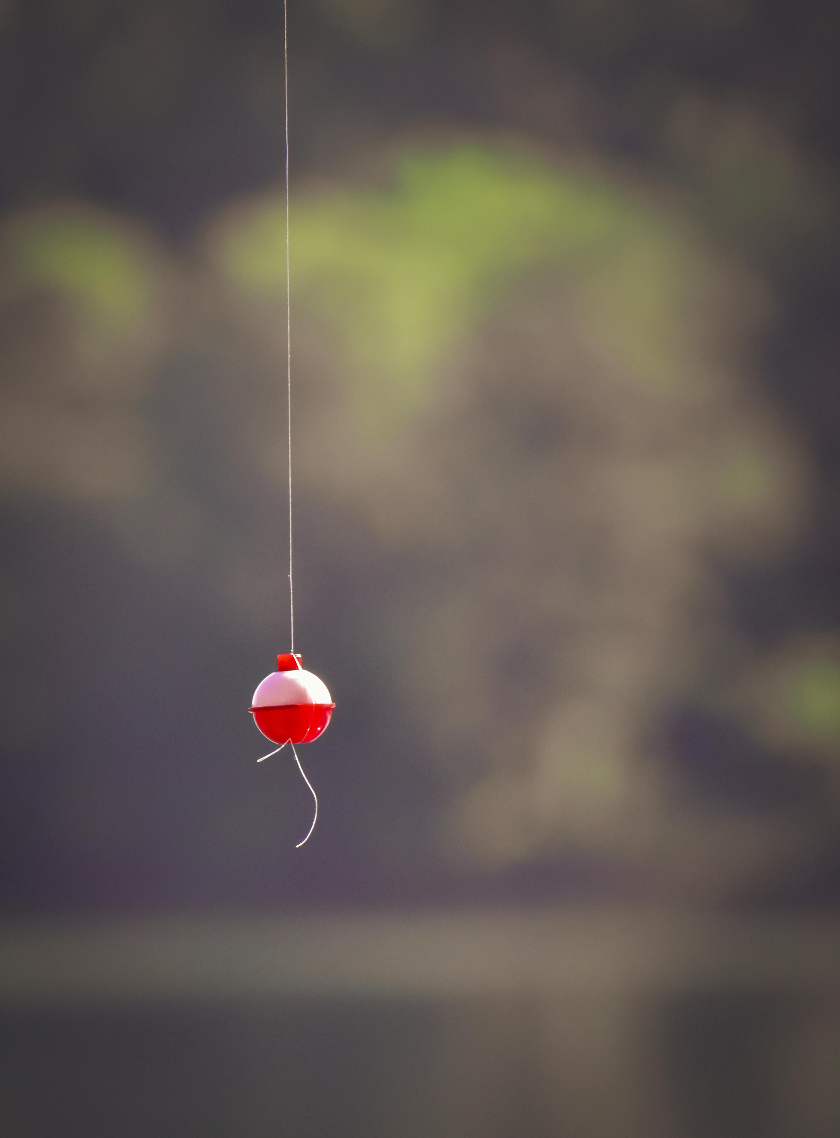 Bright red bobber hanging on thin thread · Free Stock Photo