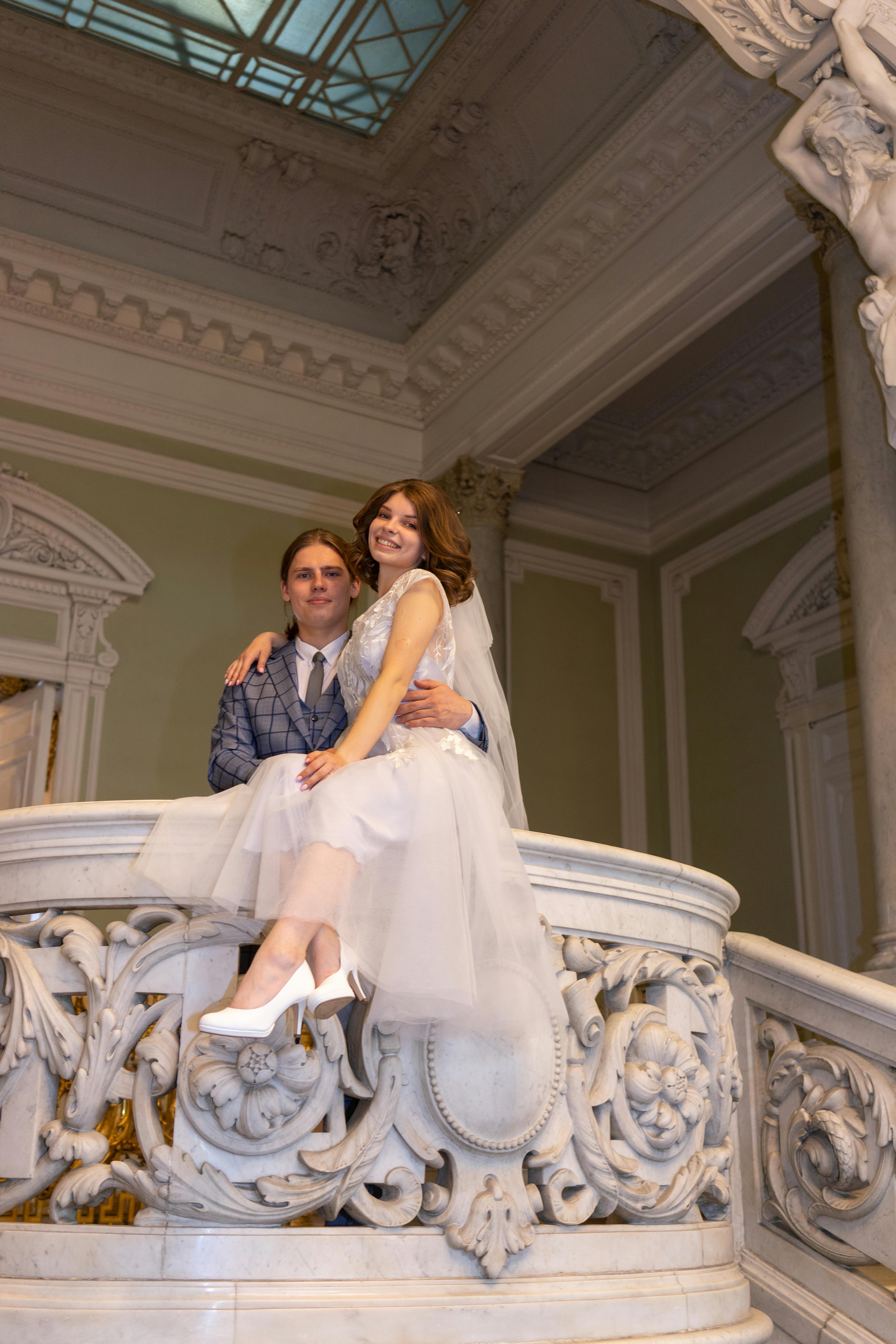 Happy newlywed couple embracing on ornamental fence in old building ...