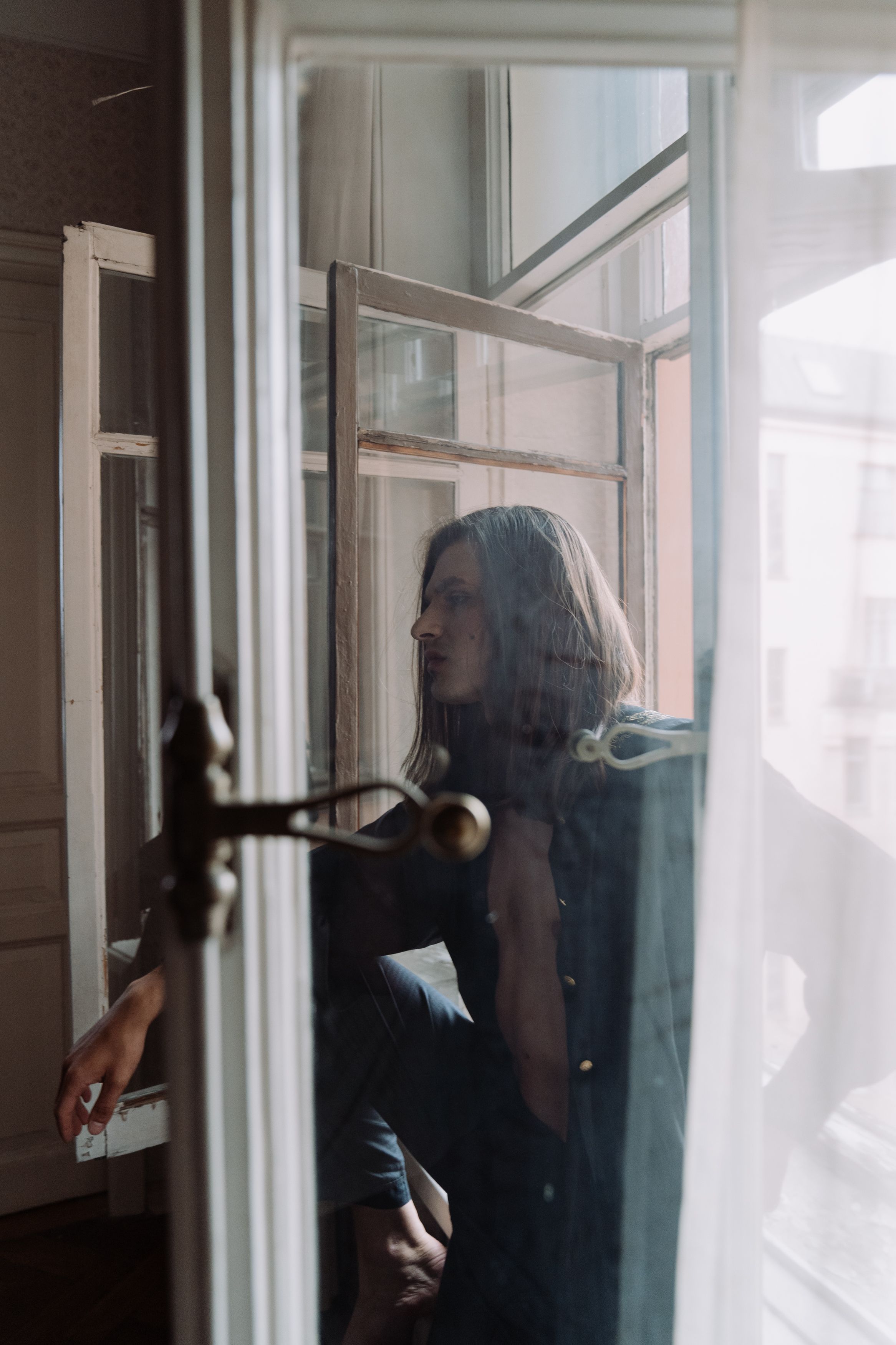 Woman in Blue Shirt Standing Beside Glass Window · Free Stock Photo