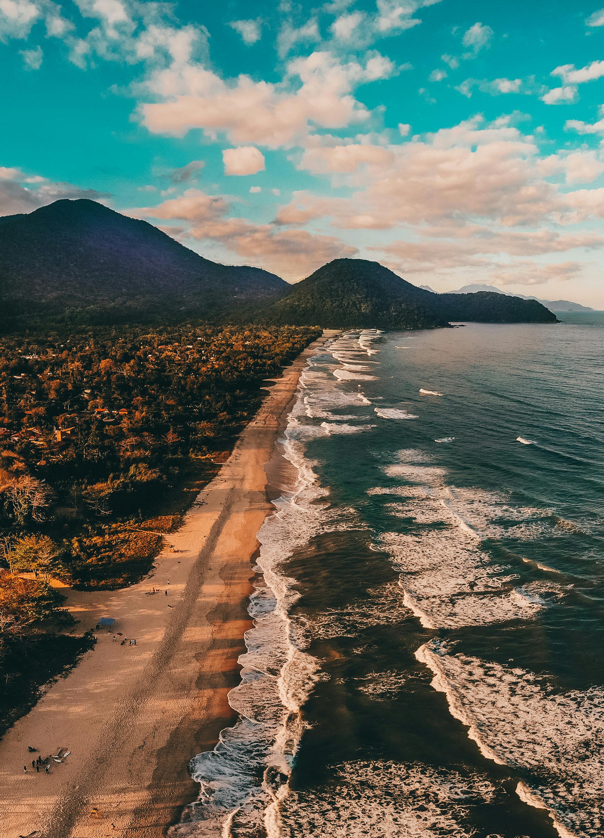 Wet sandy coast washed by azure sea in sunlight · Free Stock Photo