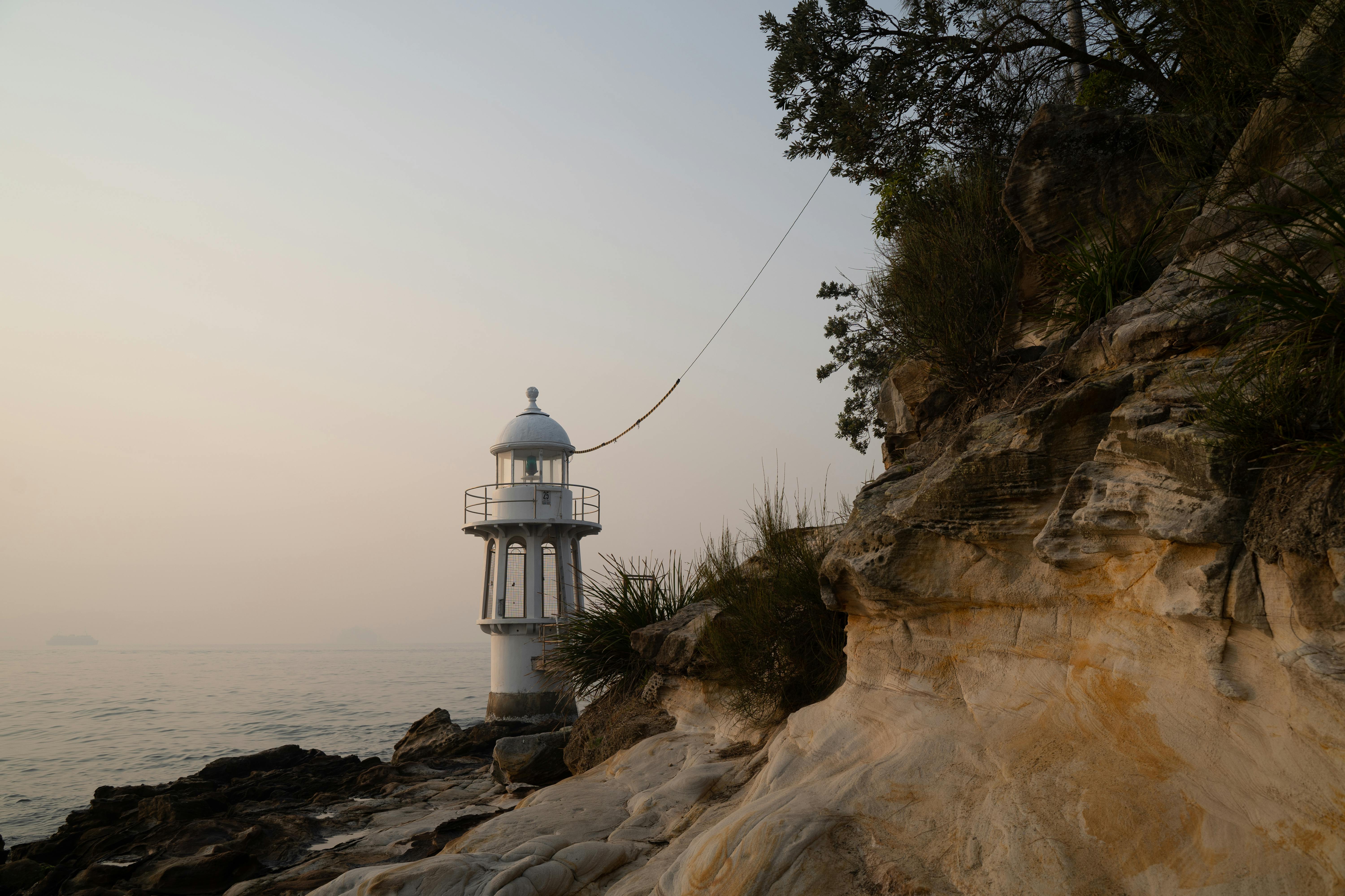 White Lighthouse on Rock Formation Near Body of Water · Free Stock Photo
