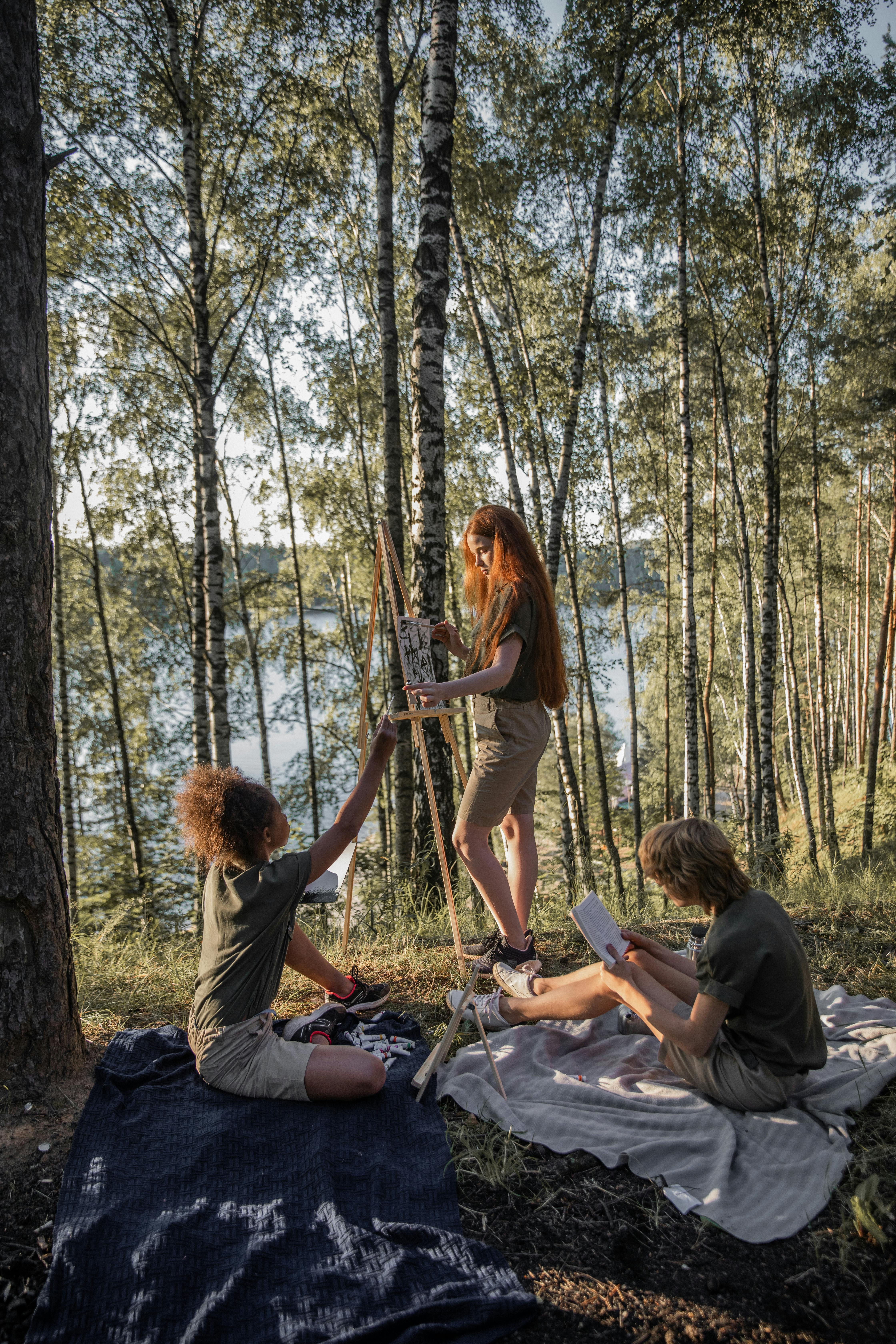 Three Young People Sitting on the Ground Surrounded by Trees · Free ...