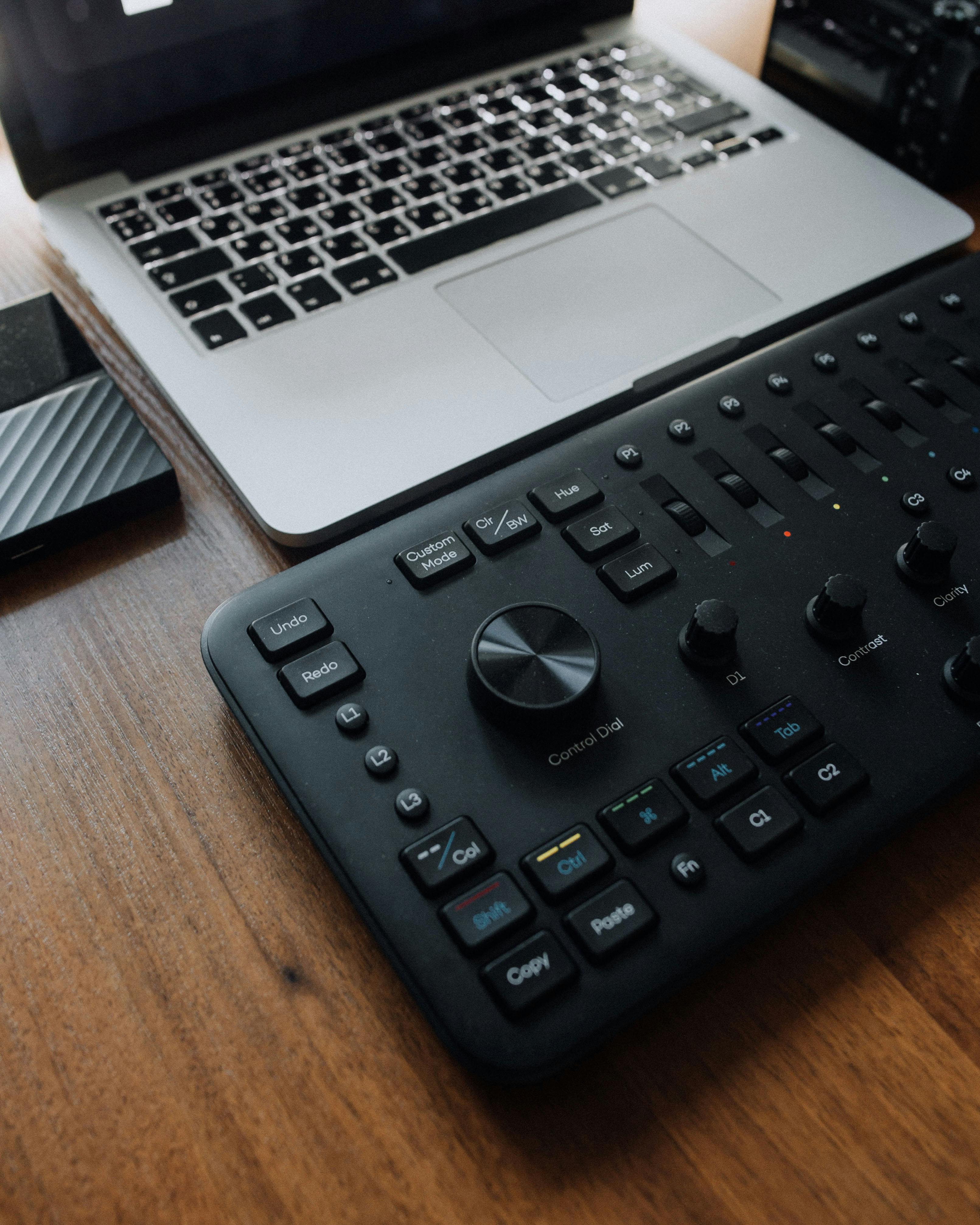 Silver Laptop Beside an Editing Console on Wooden Table · Free Stock Photo
