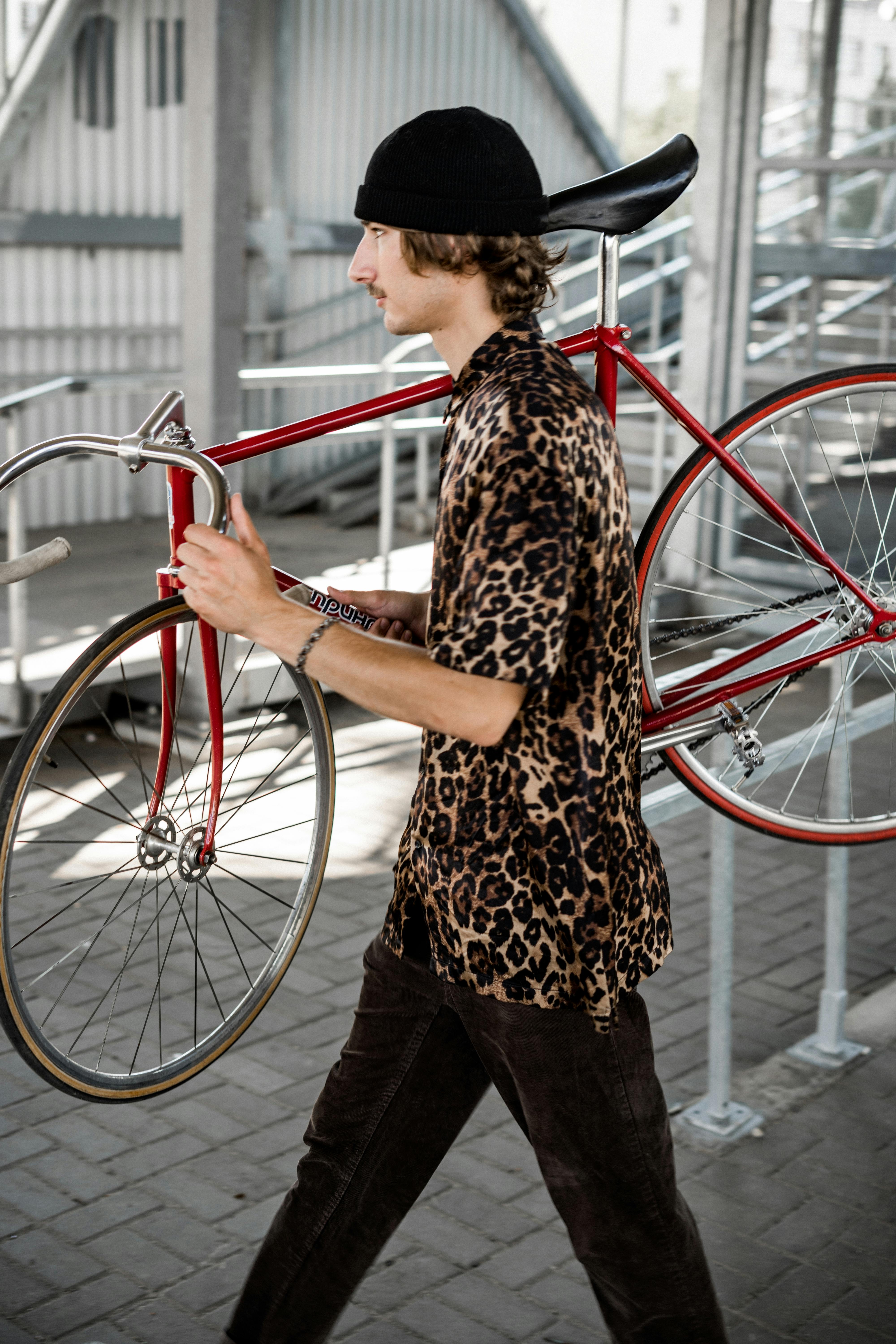 Person in Leopard Print Shirt Carrying a Bicycle · Free Stock Photo