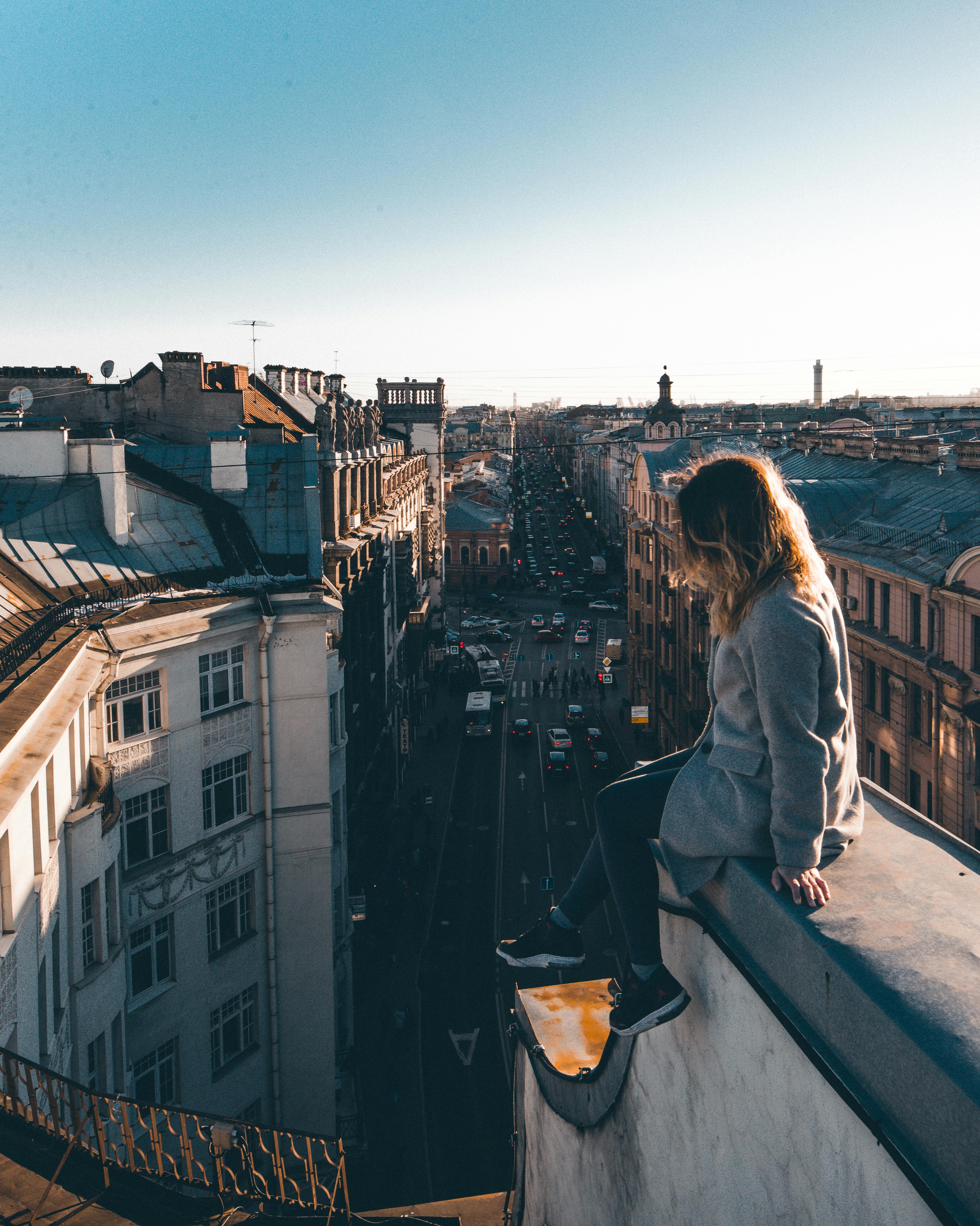 Woman Sitting on a Building Ledge · Free Stock Photo