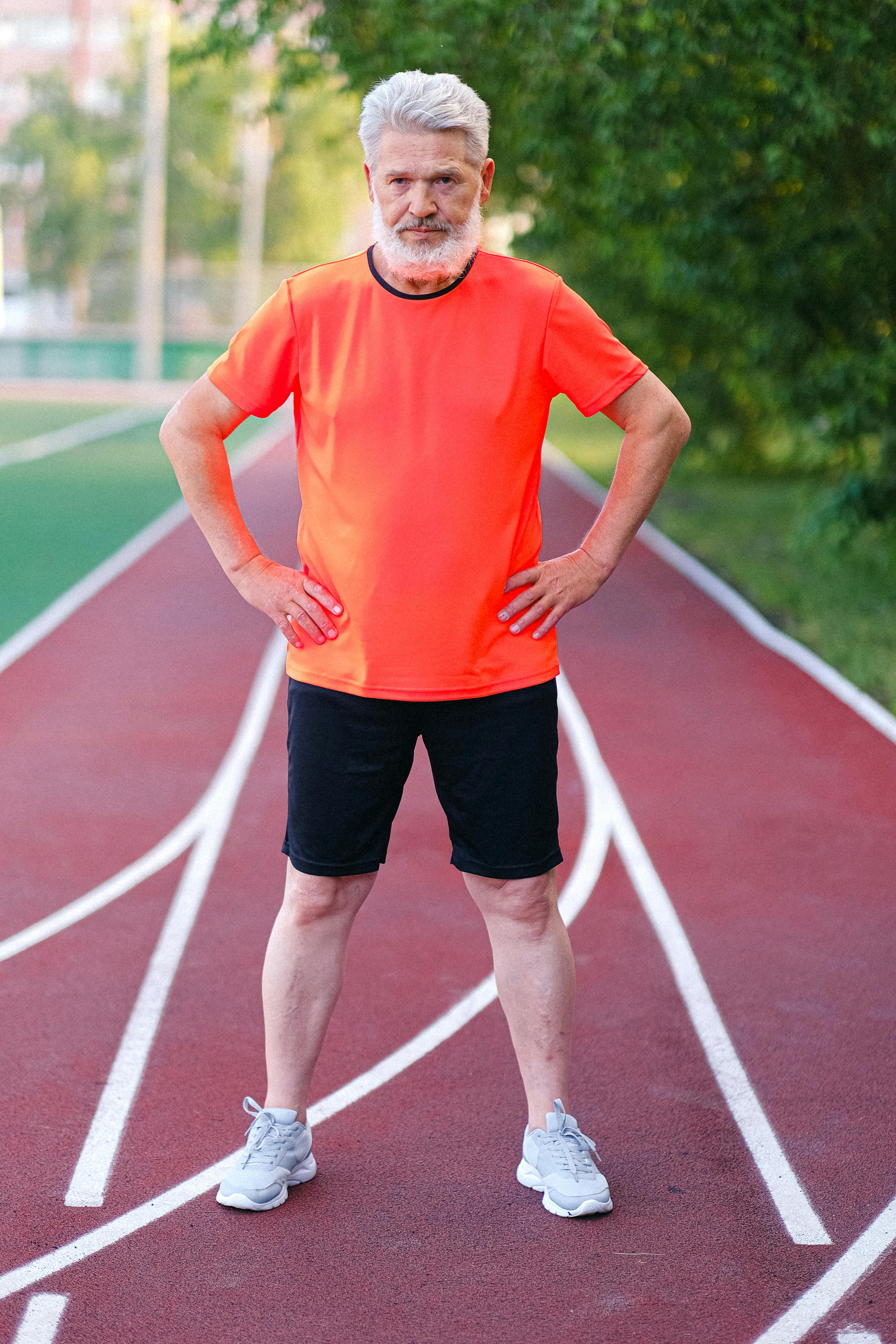 Fit runner standing on racetrack in athletics arena · Free Stock Photo