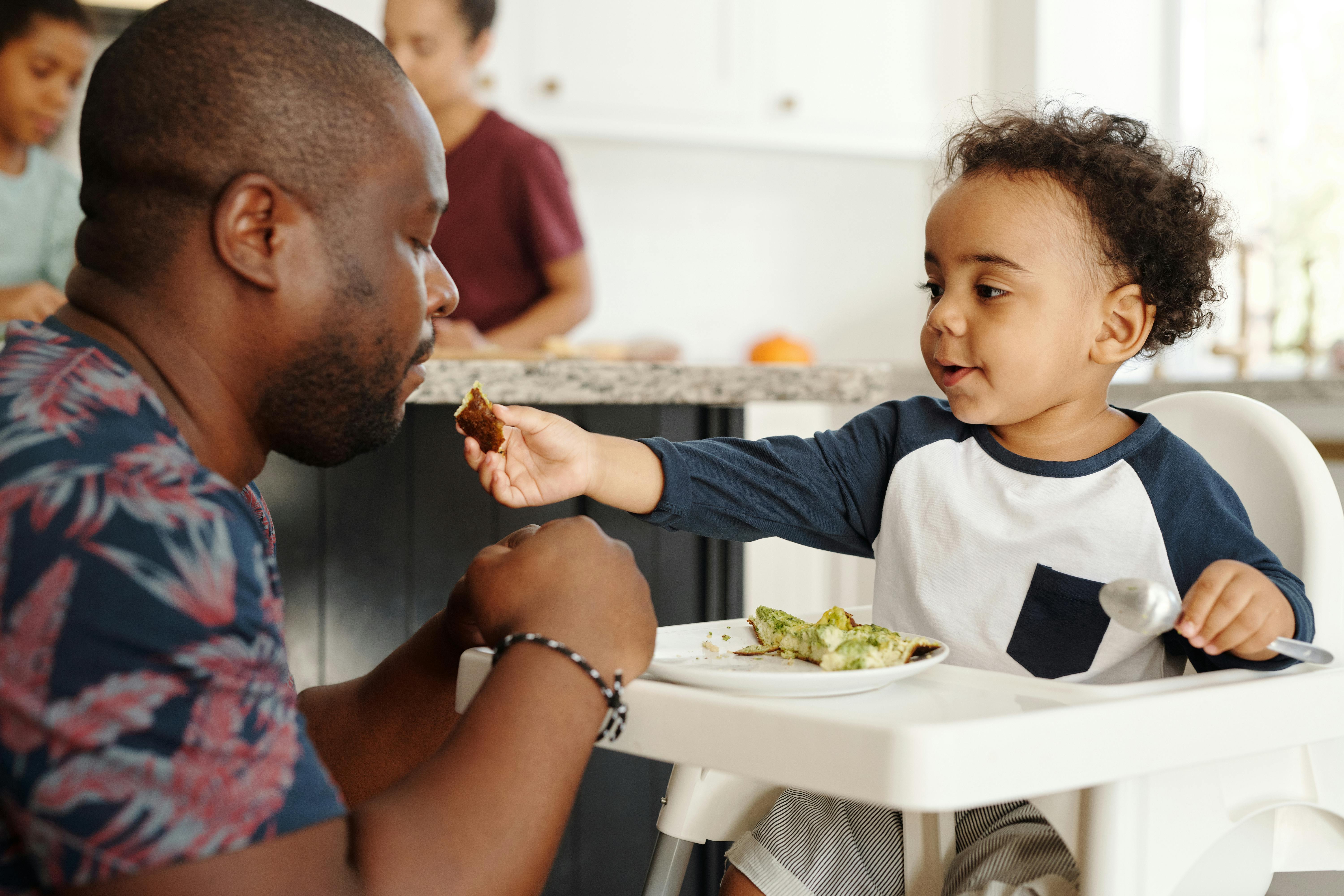 Boy Feeding Father in Kitchen · Free Stock Photo
