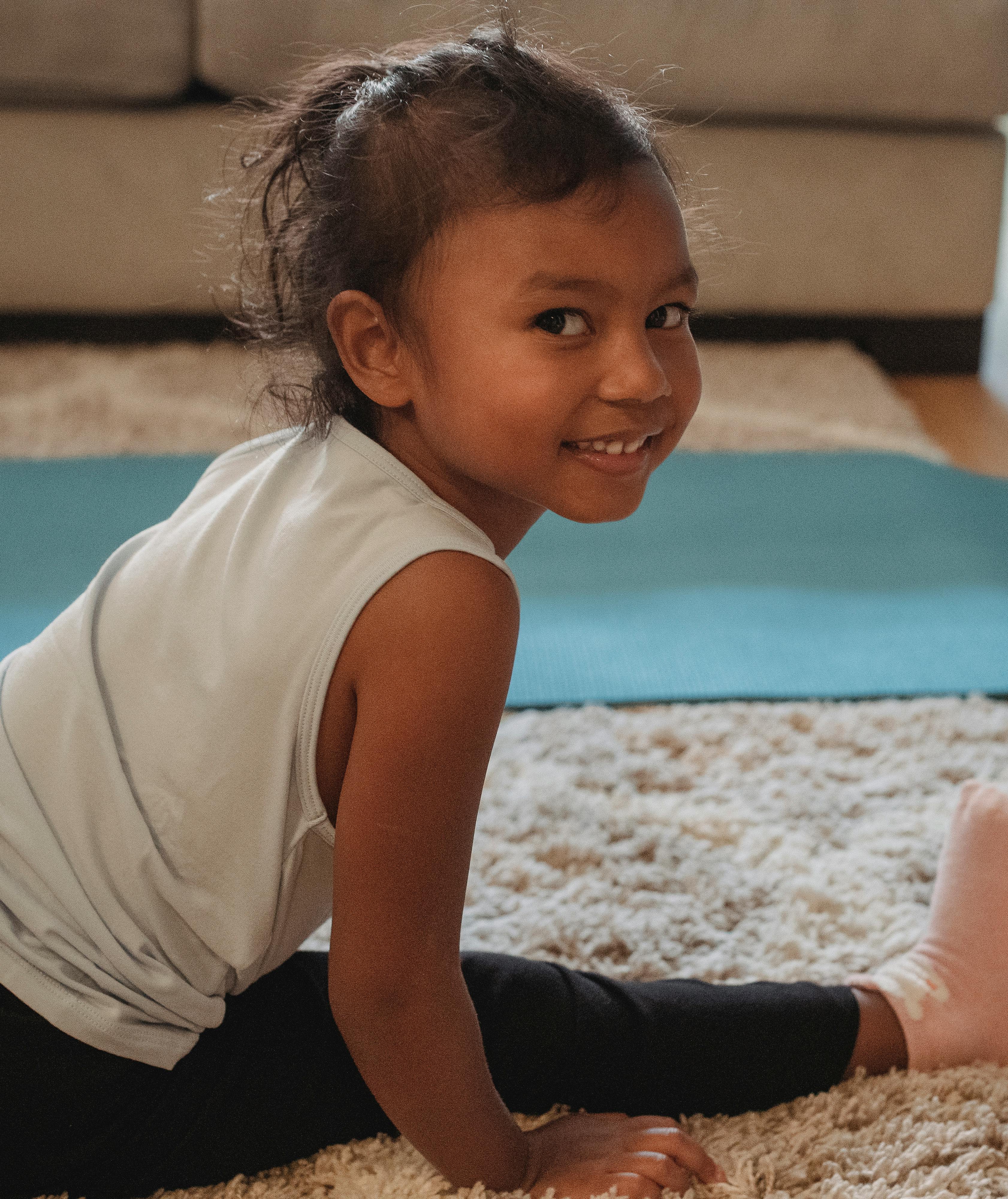Cute girl stretching on carpet · Free Stock Photo